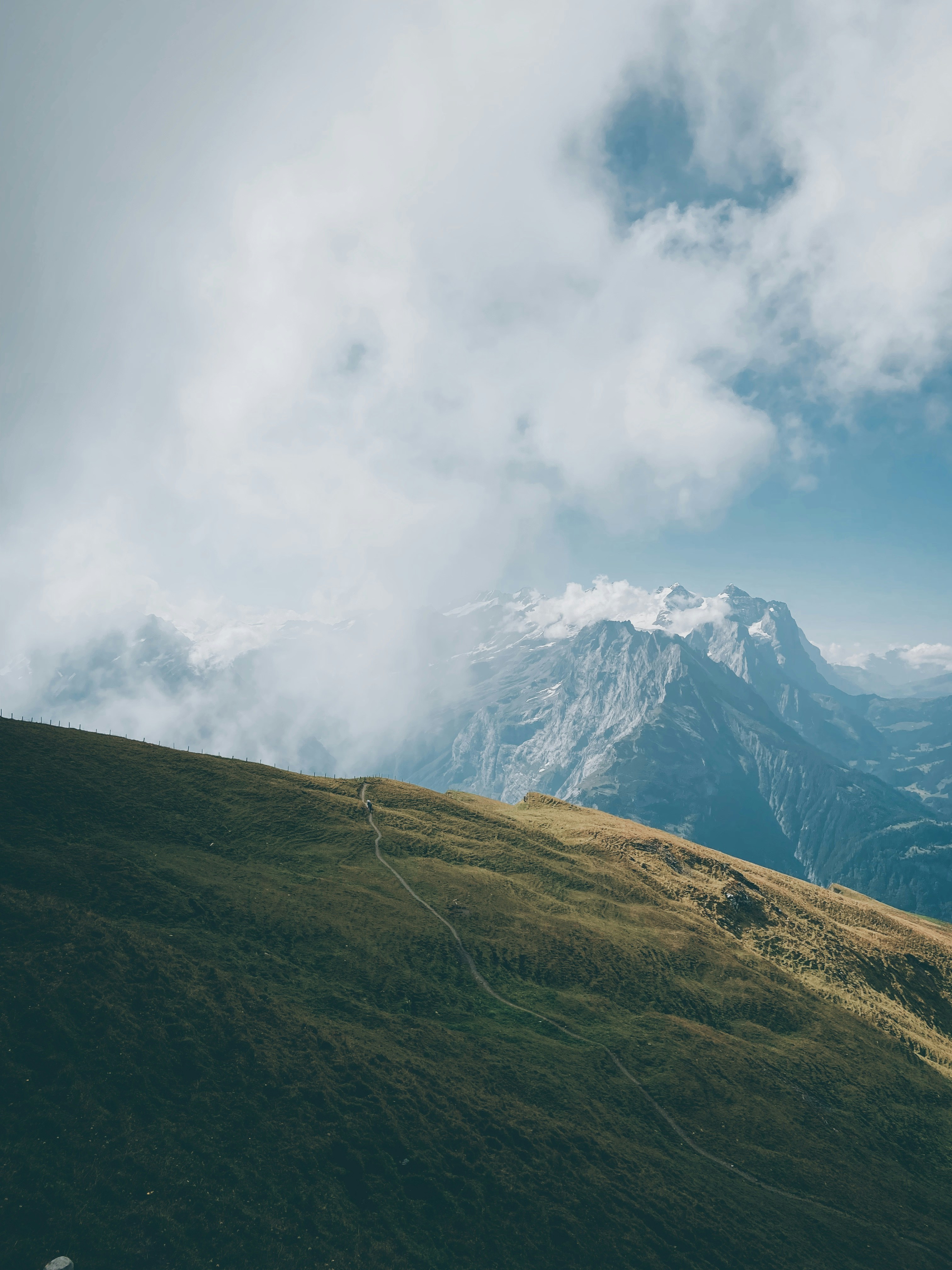 A person standing on top of a lush green hillside photo – Free ...