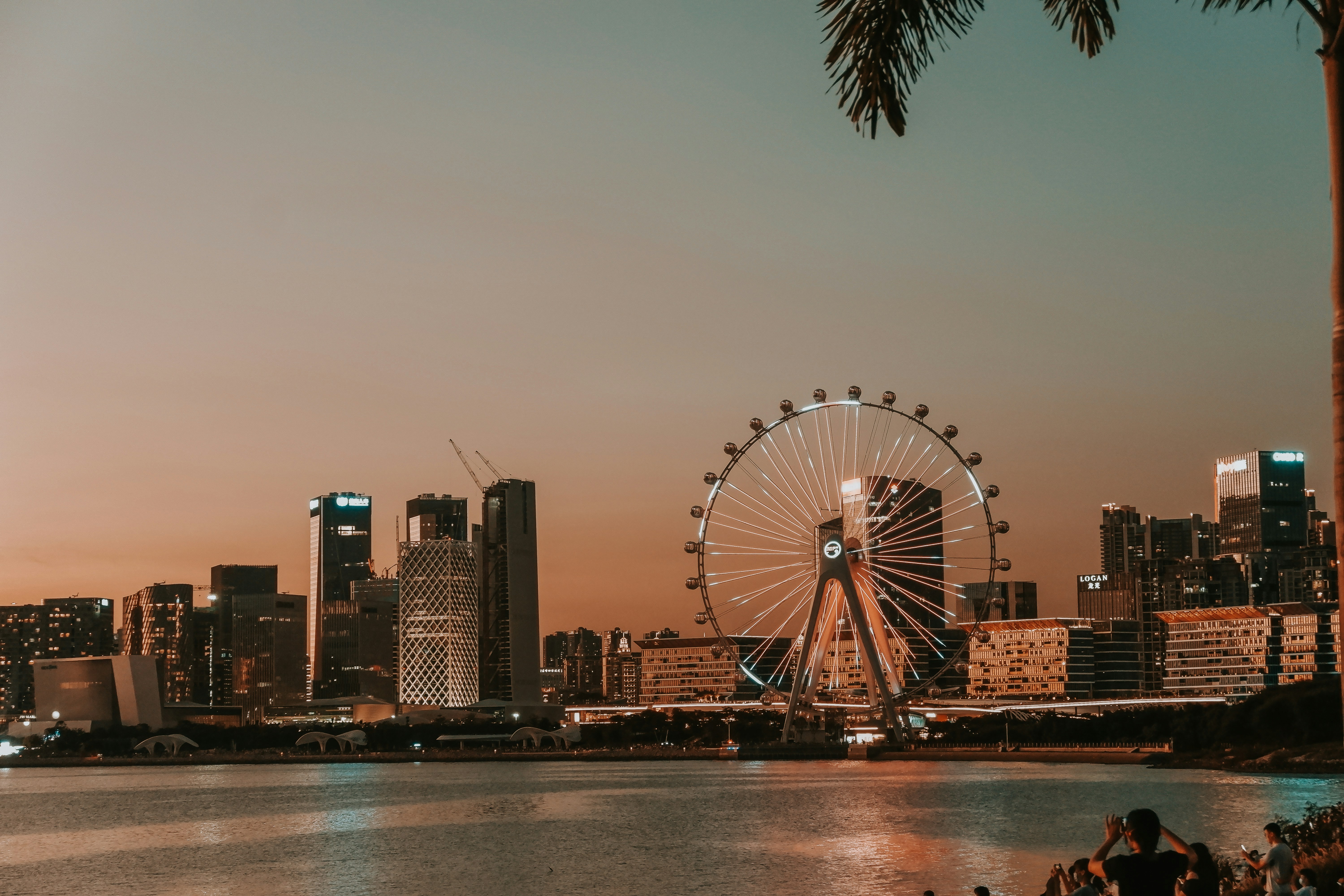 Iconic Ferris wheel illuminated against a twilight skyline, showcasing urban life and leisure by the water's edge.