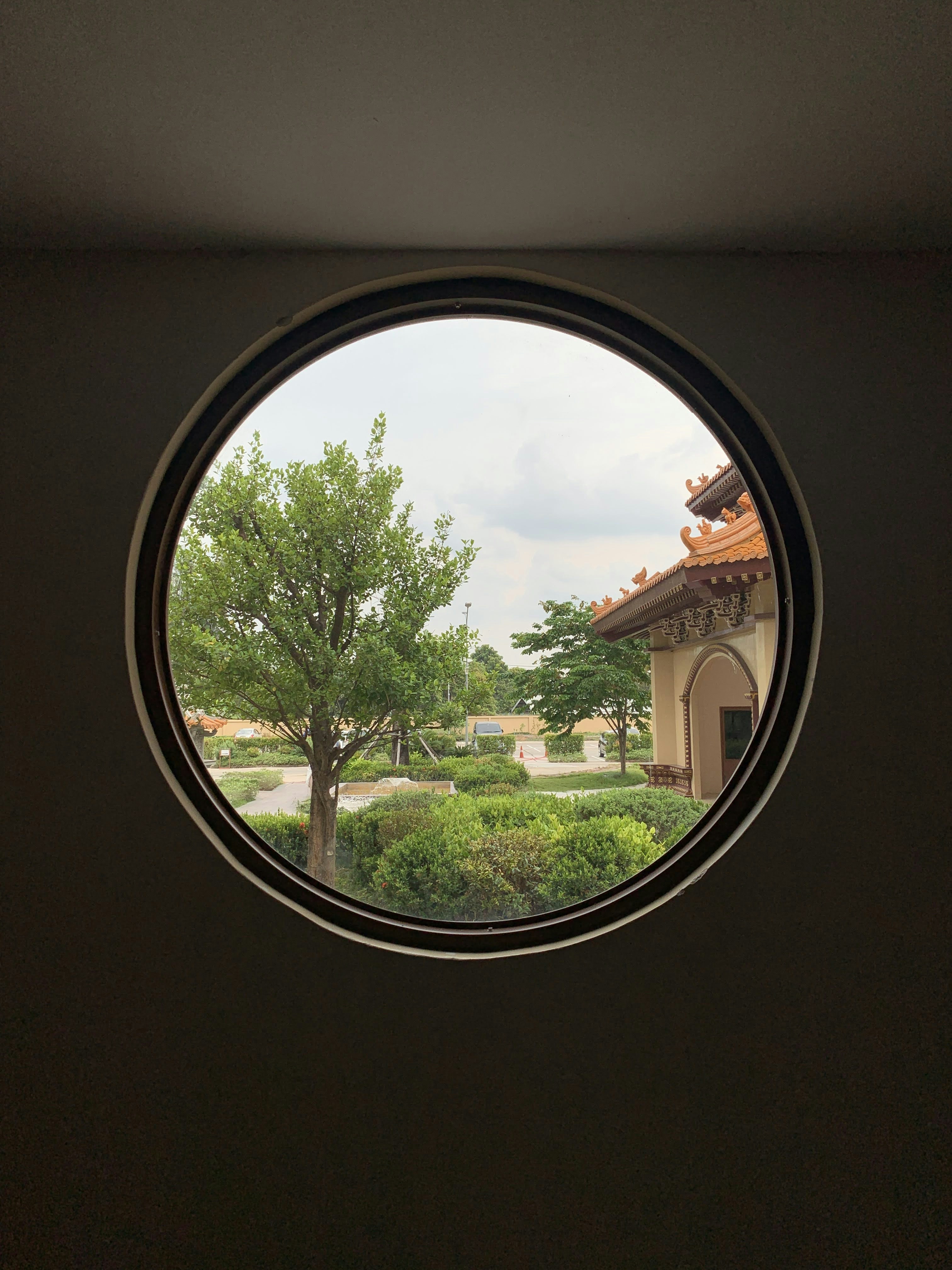 A view of a tree through a round window photo – Free Temple Image on ...