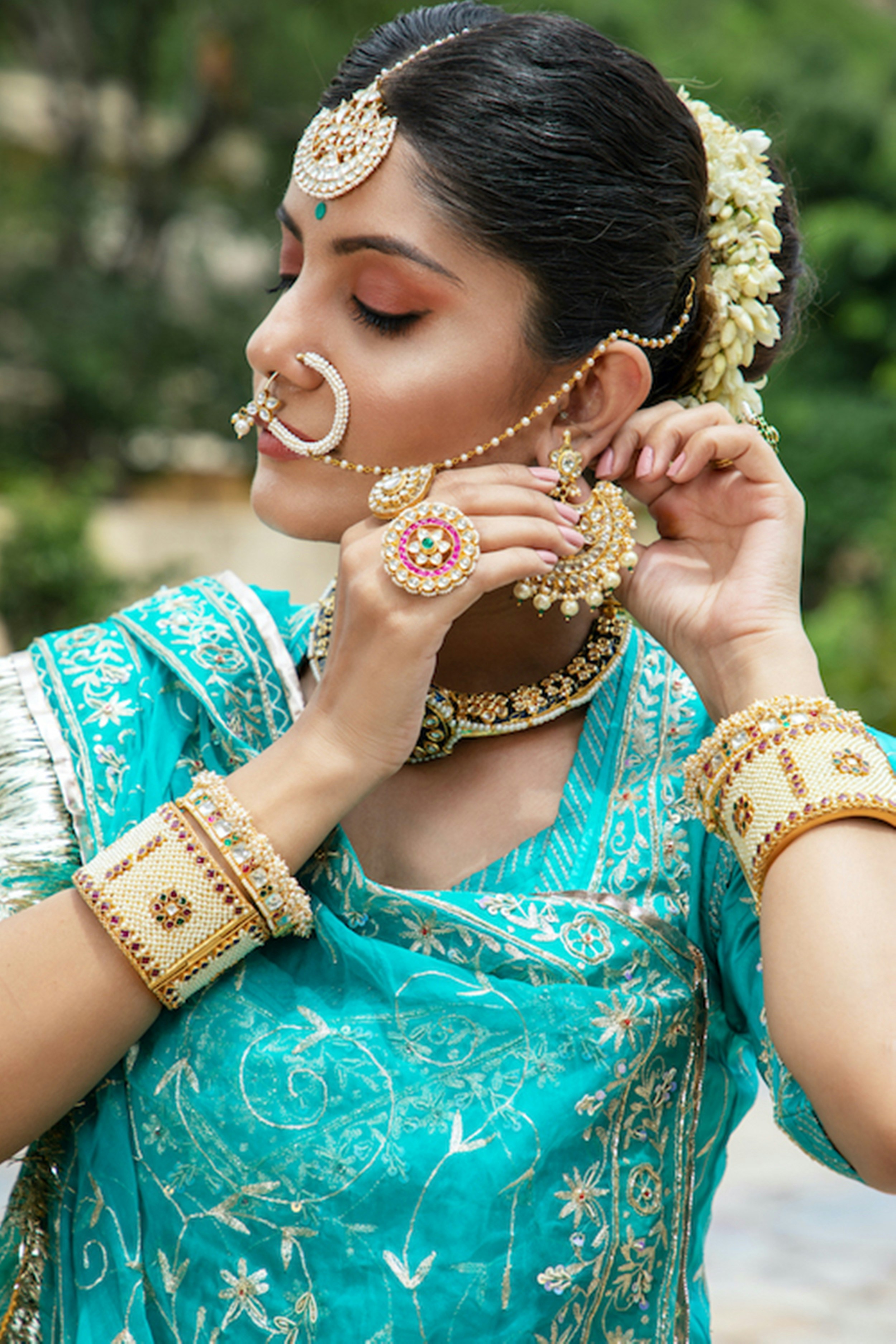 A woman adorned in traditional attire adjusts her intricate jewelry, showcasing cultural heritage and craftsmanship.
