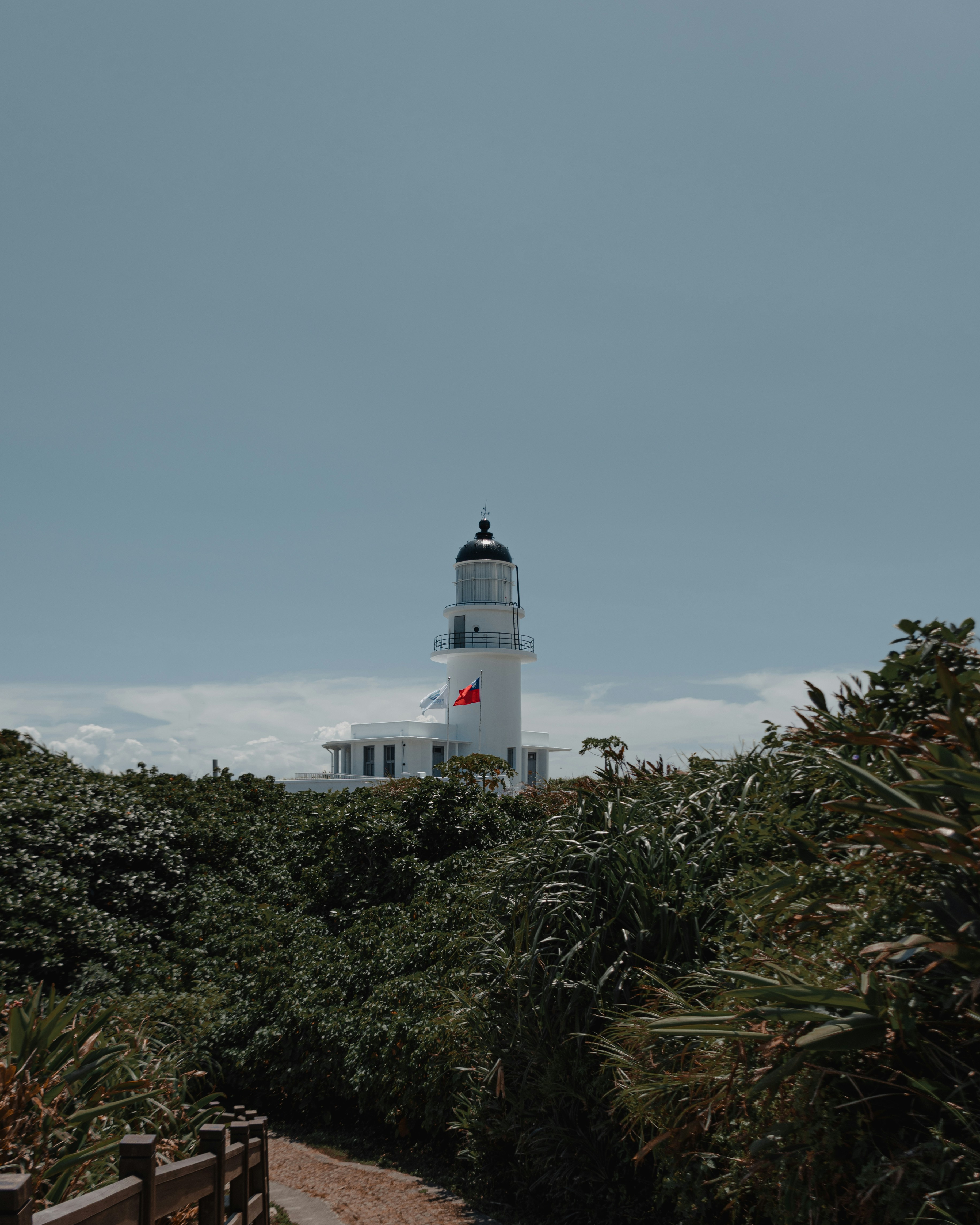 a white lighthouse with a red flag on top of it