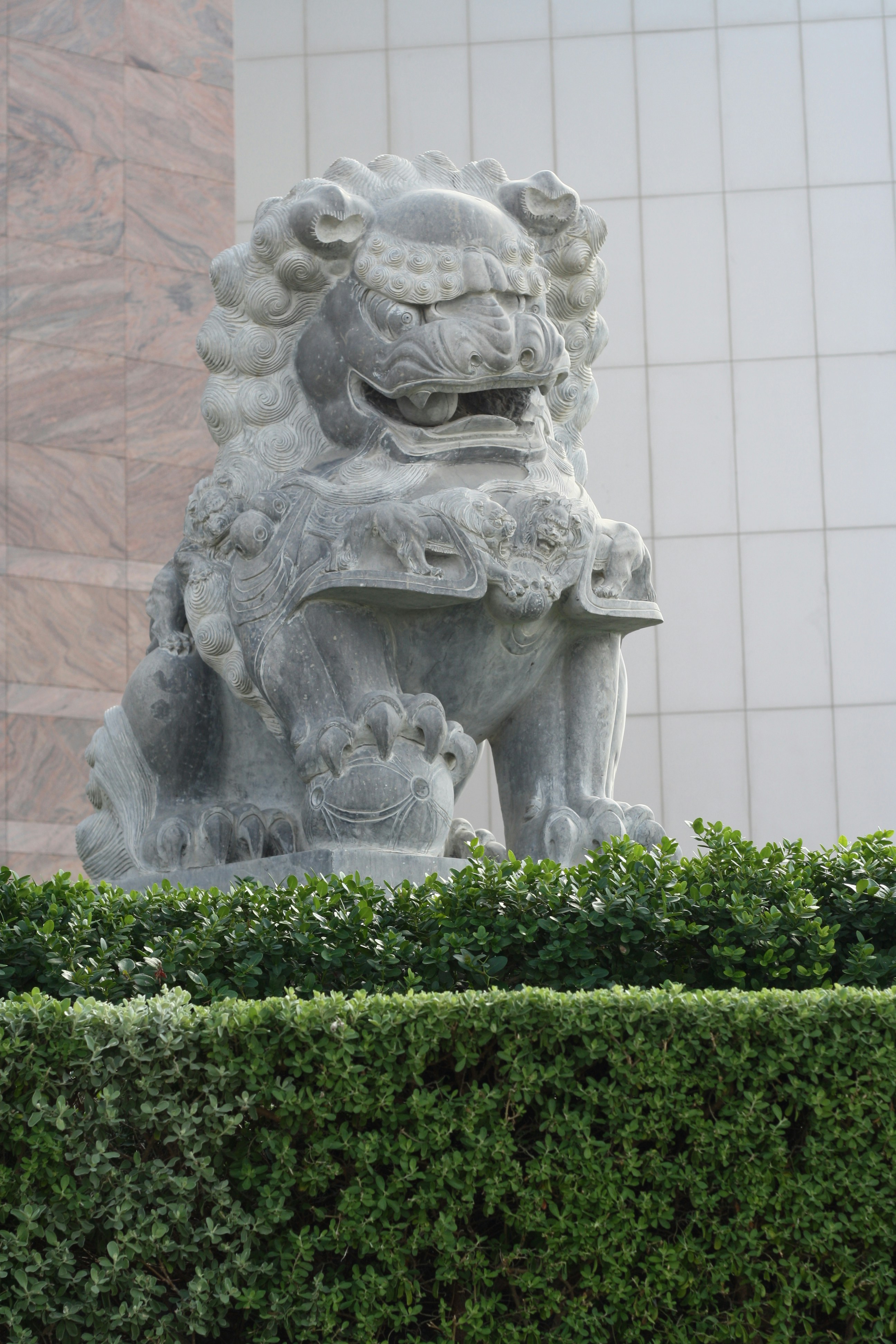 A majestic stone lion statue, intricately carved, perched amidst lush greenery, symbolizing protection and strength.
