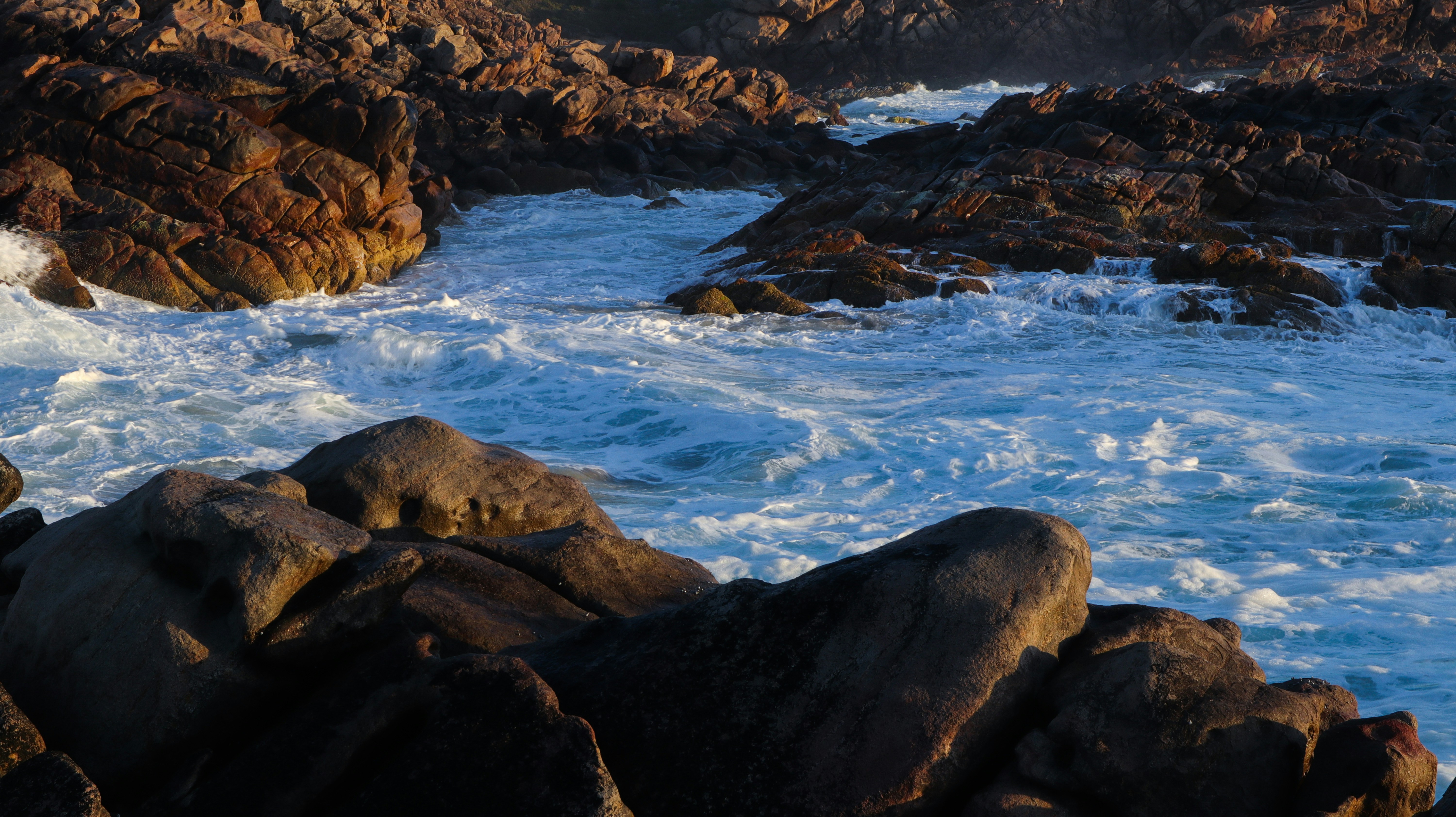 A rocky shore with waves crashing against the rocks photo – Free ...