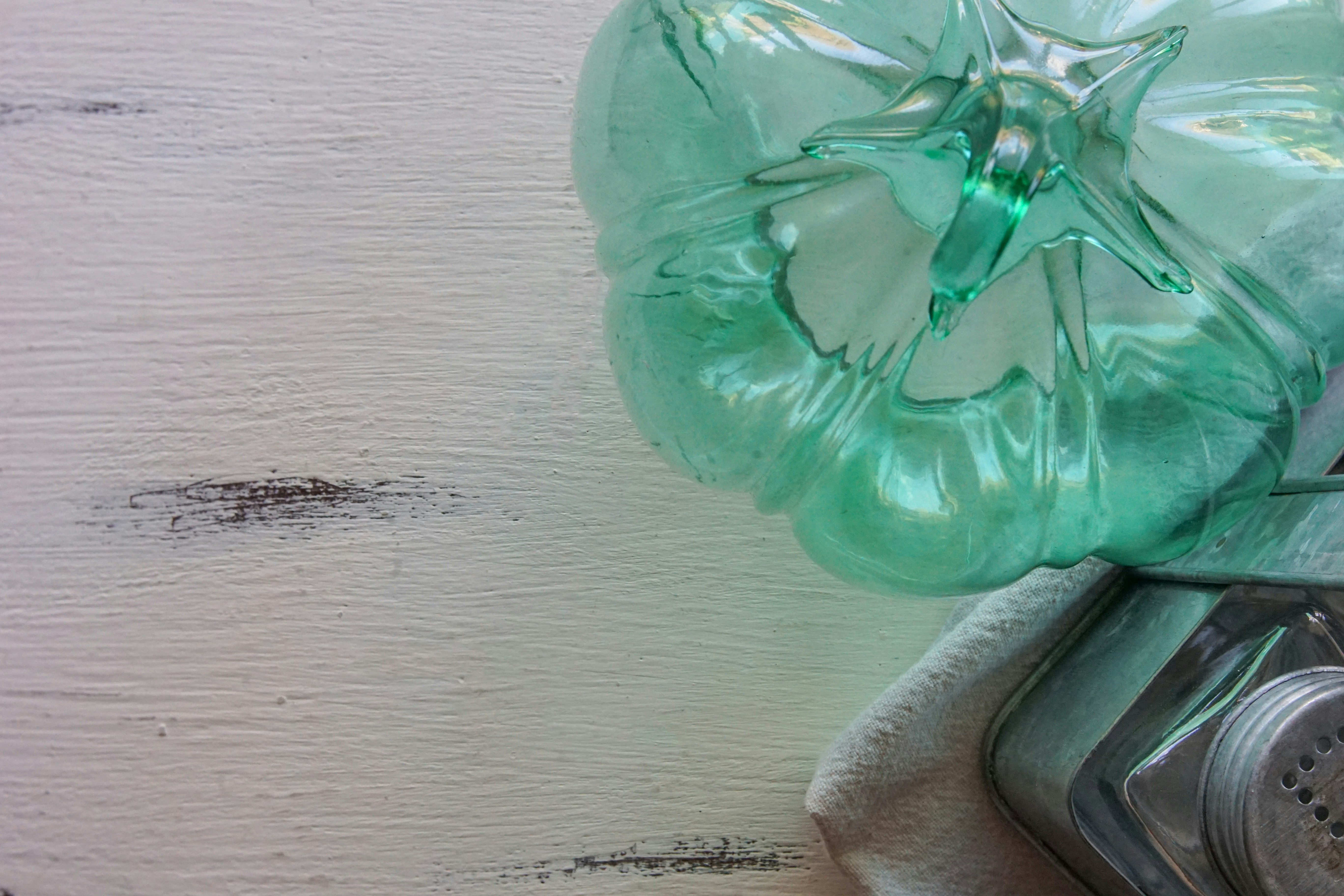 Emerald Balloon Resting on Weathered Wood Beside a Shiny Salt Shaker