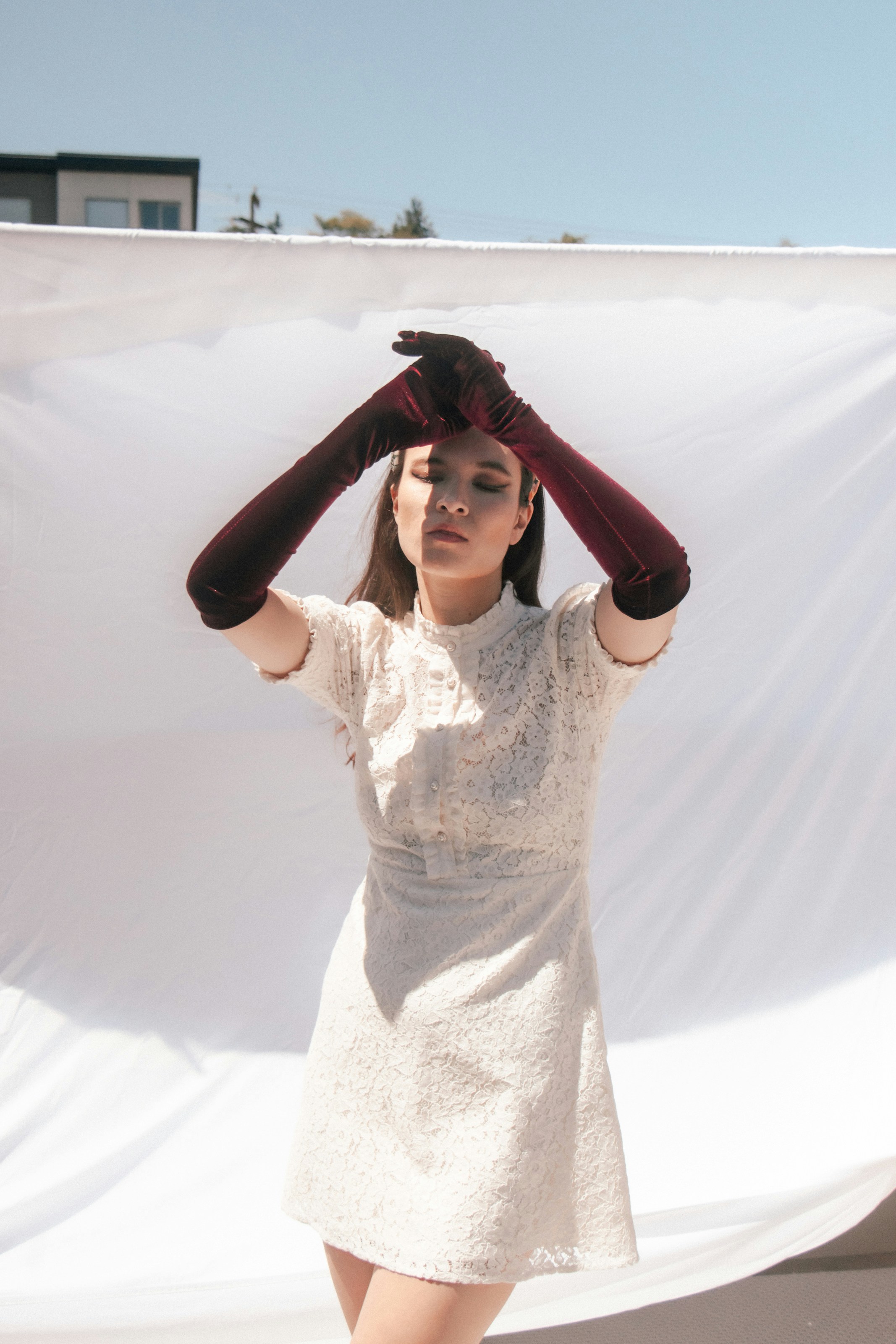 Gloves Raised, White Dress Under Bright Sky