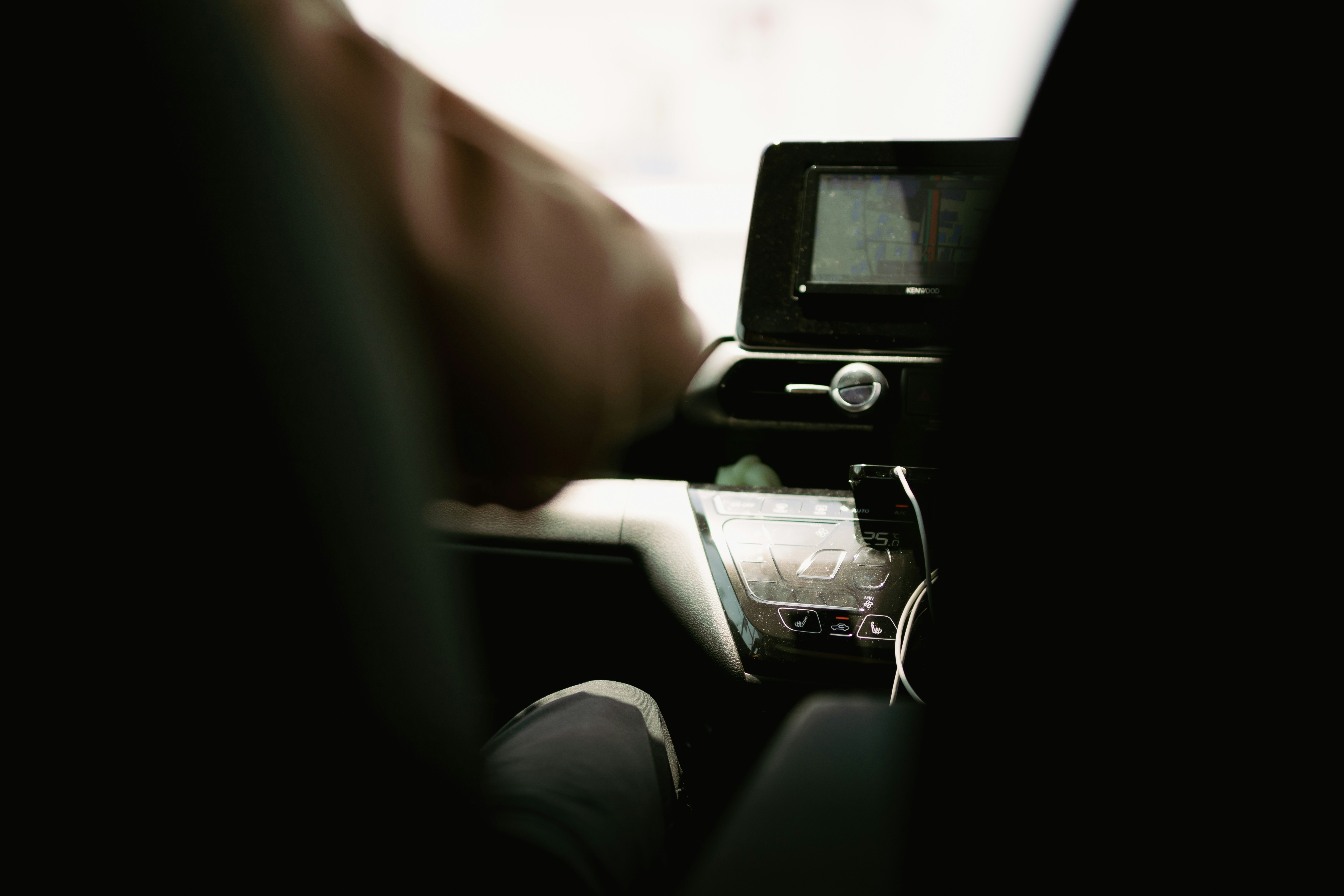 Interior view of a modern car showcasing the dashboard and navigation system, with a focus on the driver's hand reaching for controls.