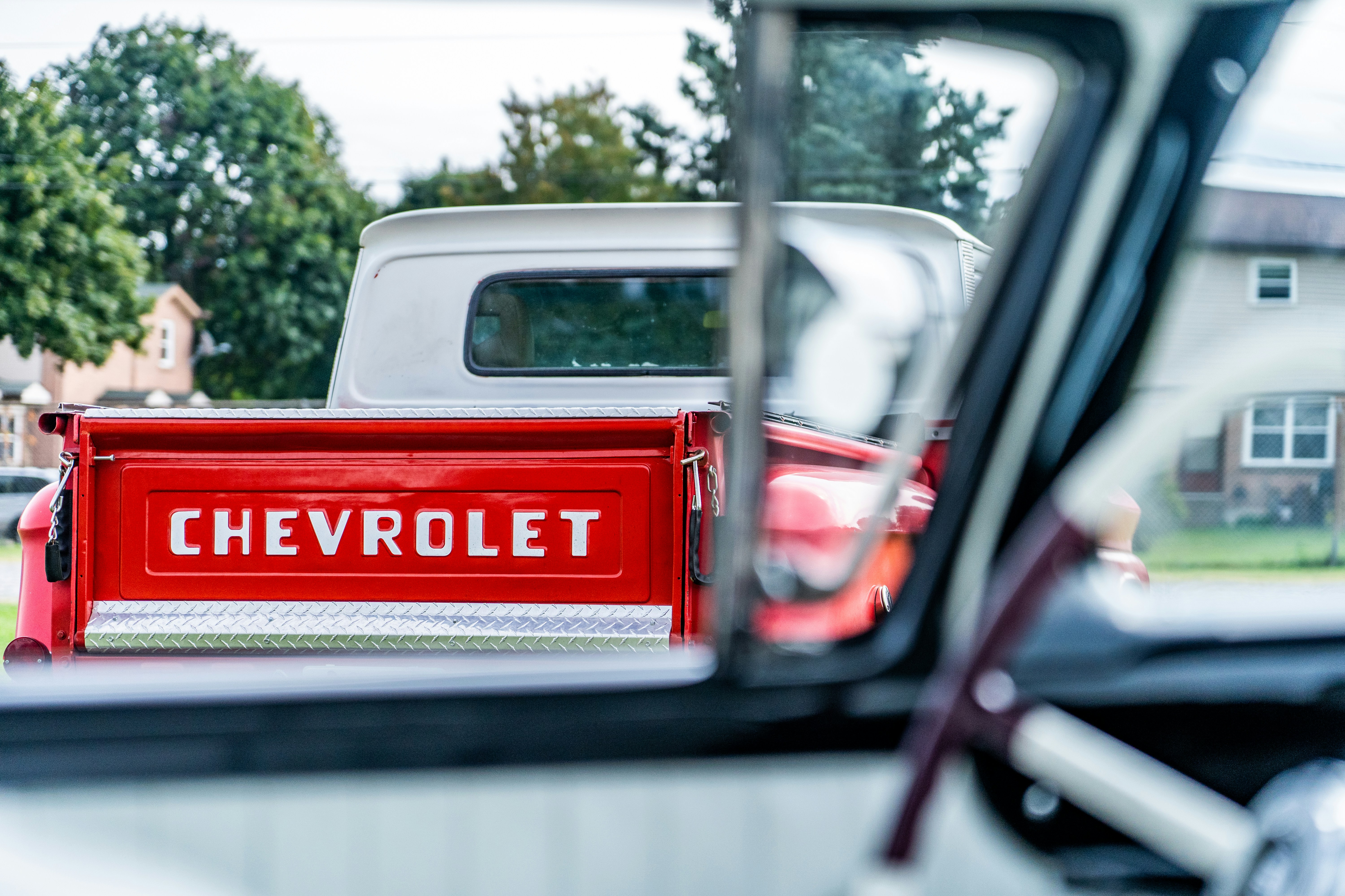 Classic Chevrolet truck viewed through the window of another vehicle, showcasing its vibrant red color and vintage charm.
