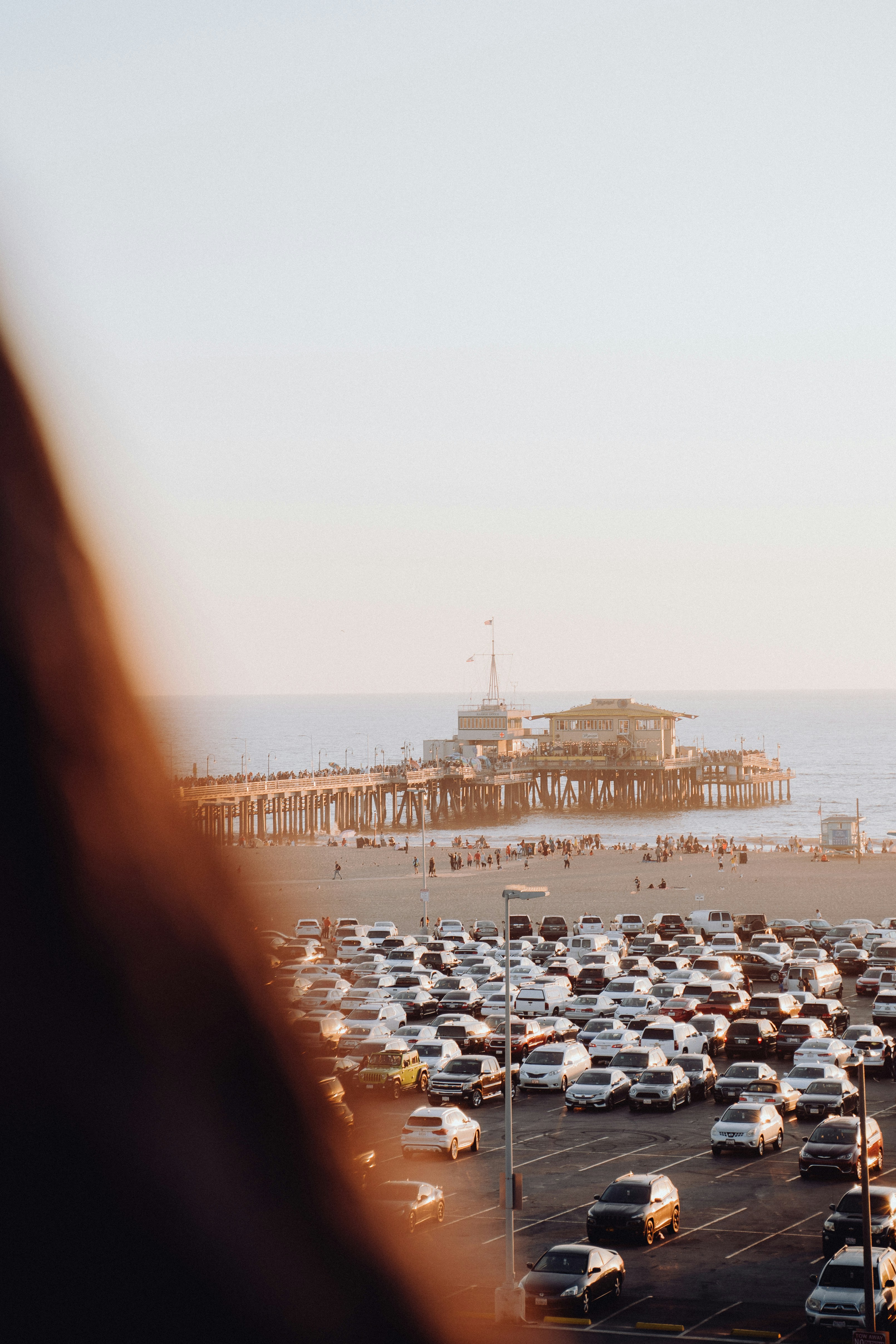End of the Pier: Golden Hour Convergence of Cars and Beachgoers