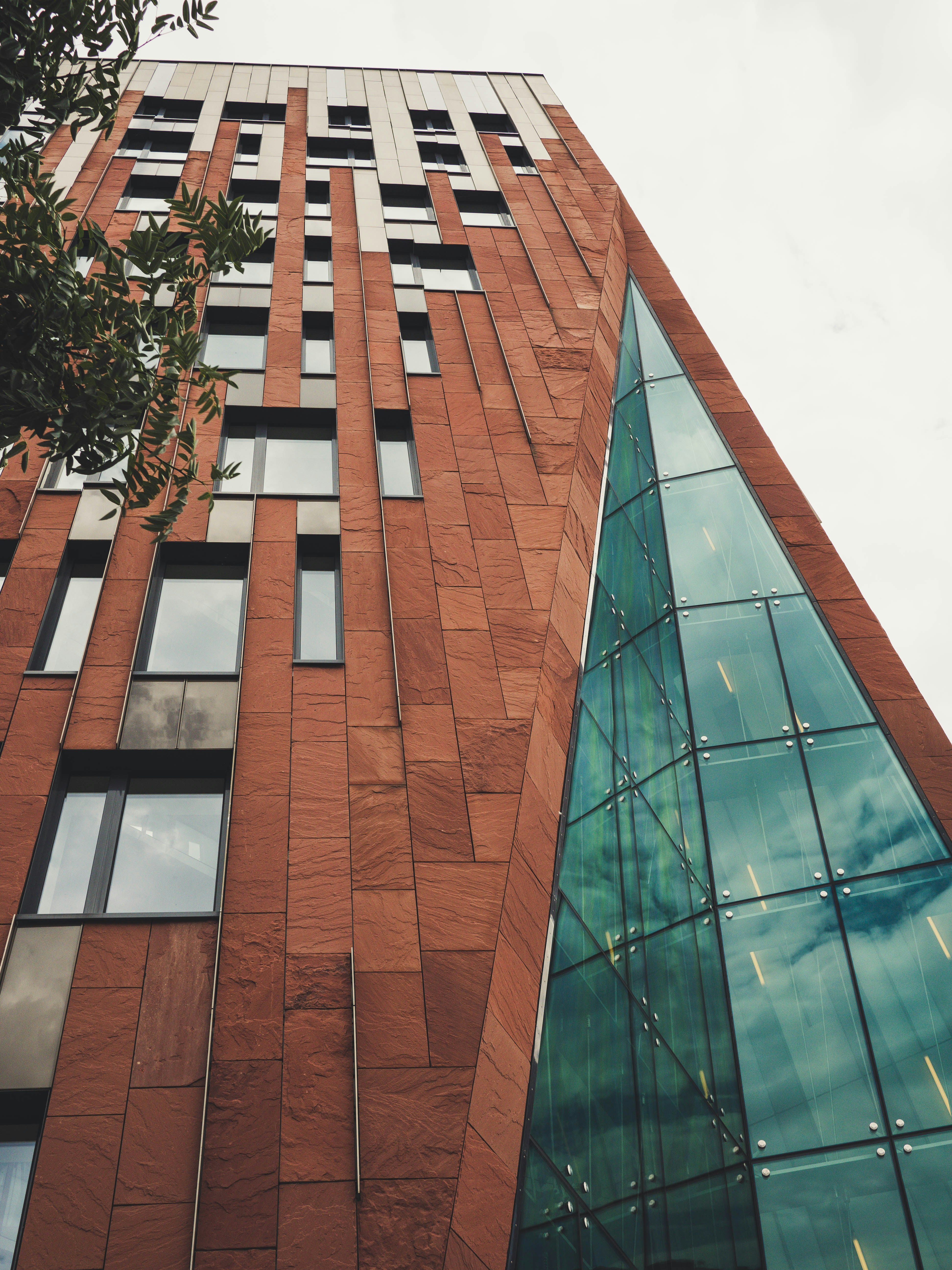 A tall red brick building next to a tree photo – Free Modern ...