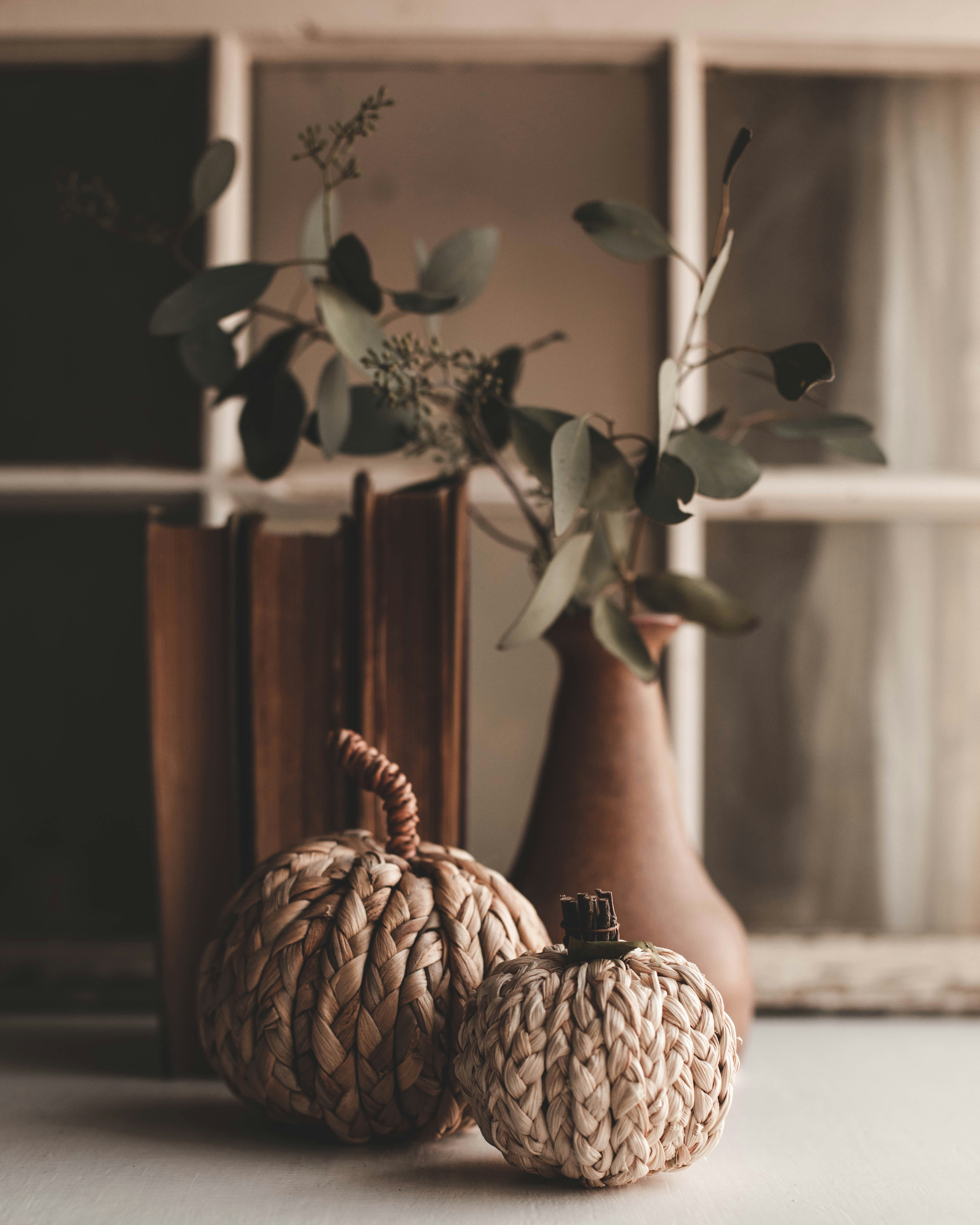 Woven pumpkins and a vase of eucalyptus create a warm, inviting atmosphere in a cozy indoor setting.