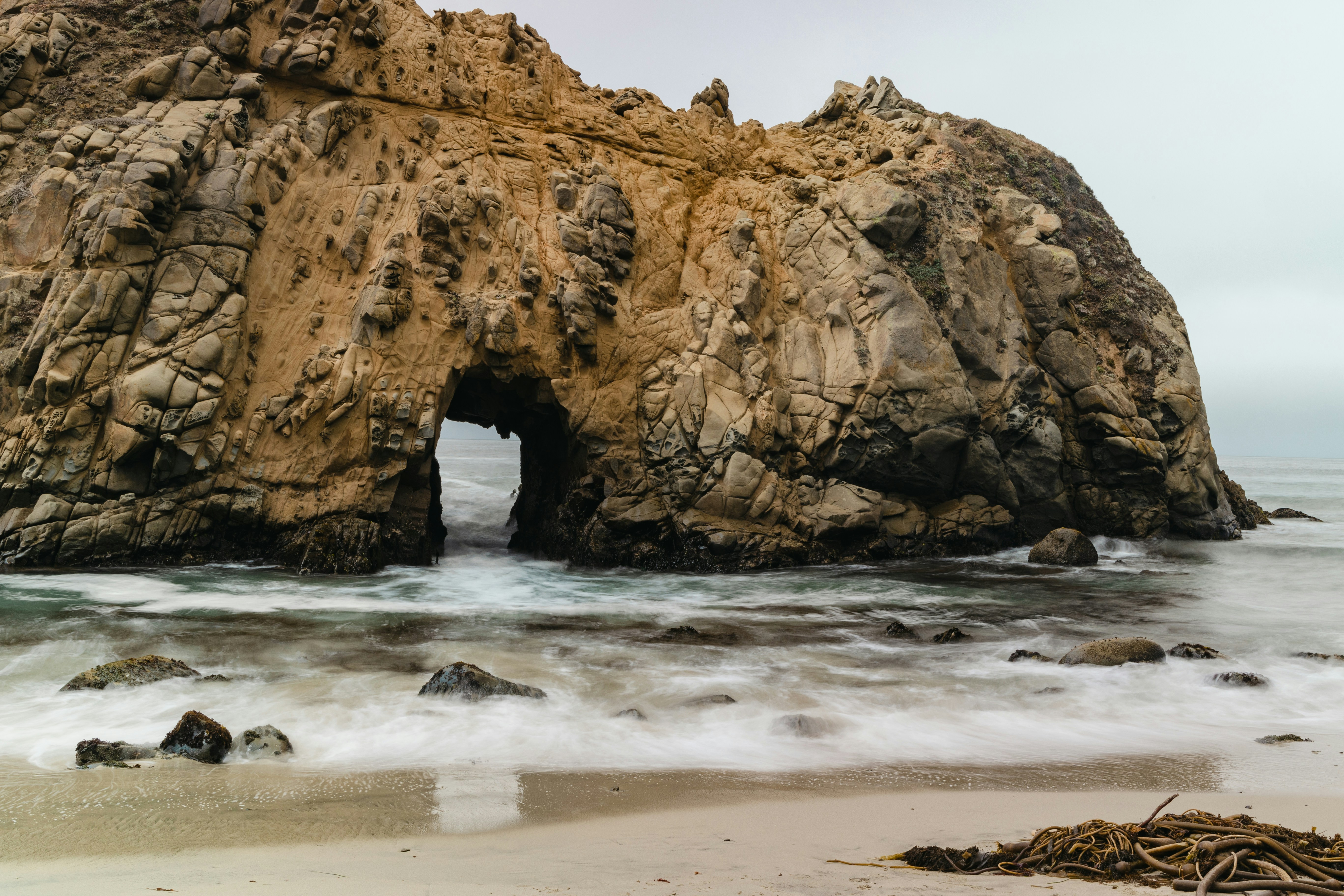 Un gros rocher sortant de l’océan à côté d’une plage photo – Photo ...