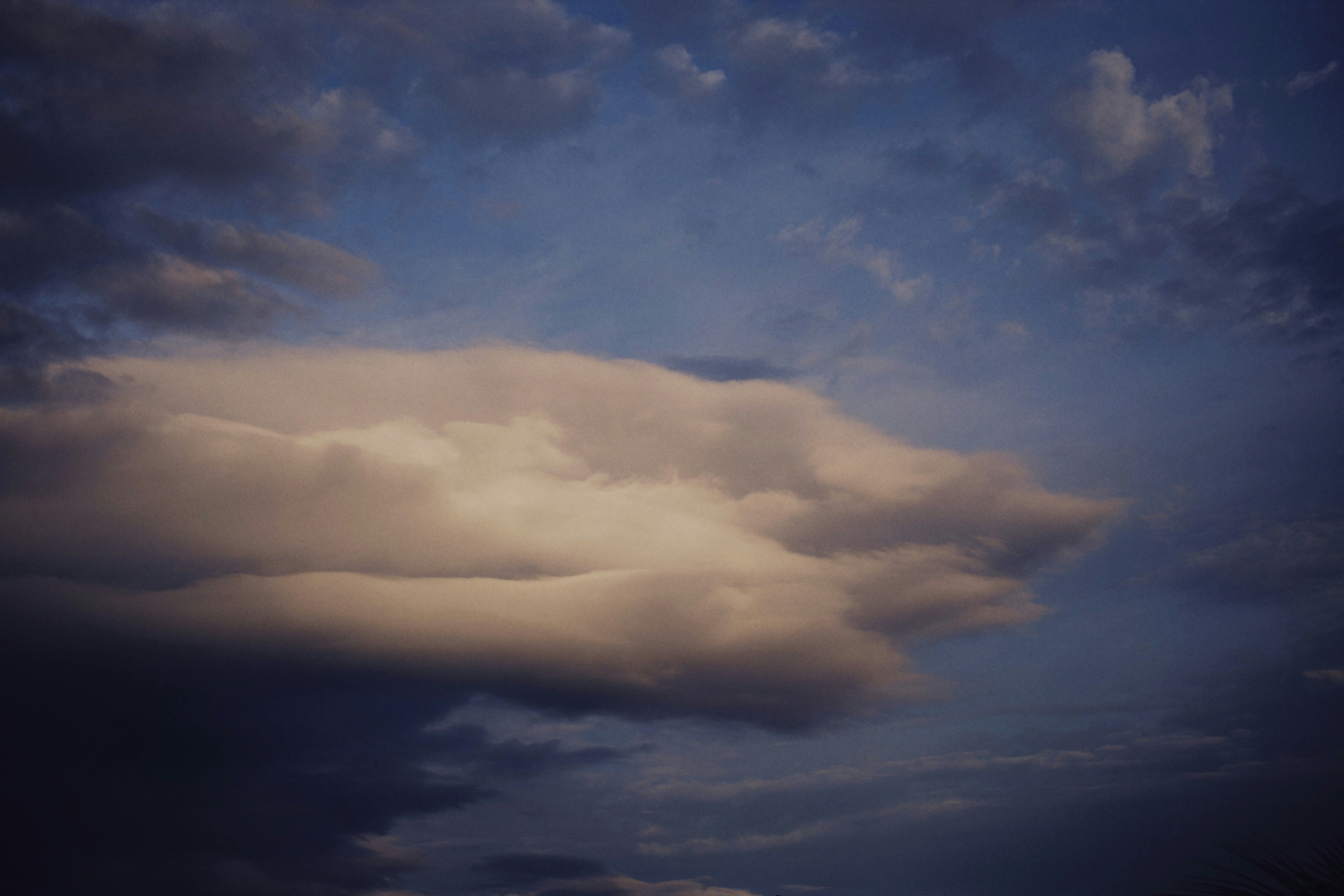 A cloudy sky with a plane flying in the distance photo – Free Nature ...