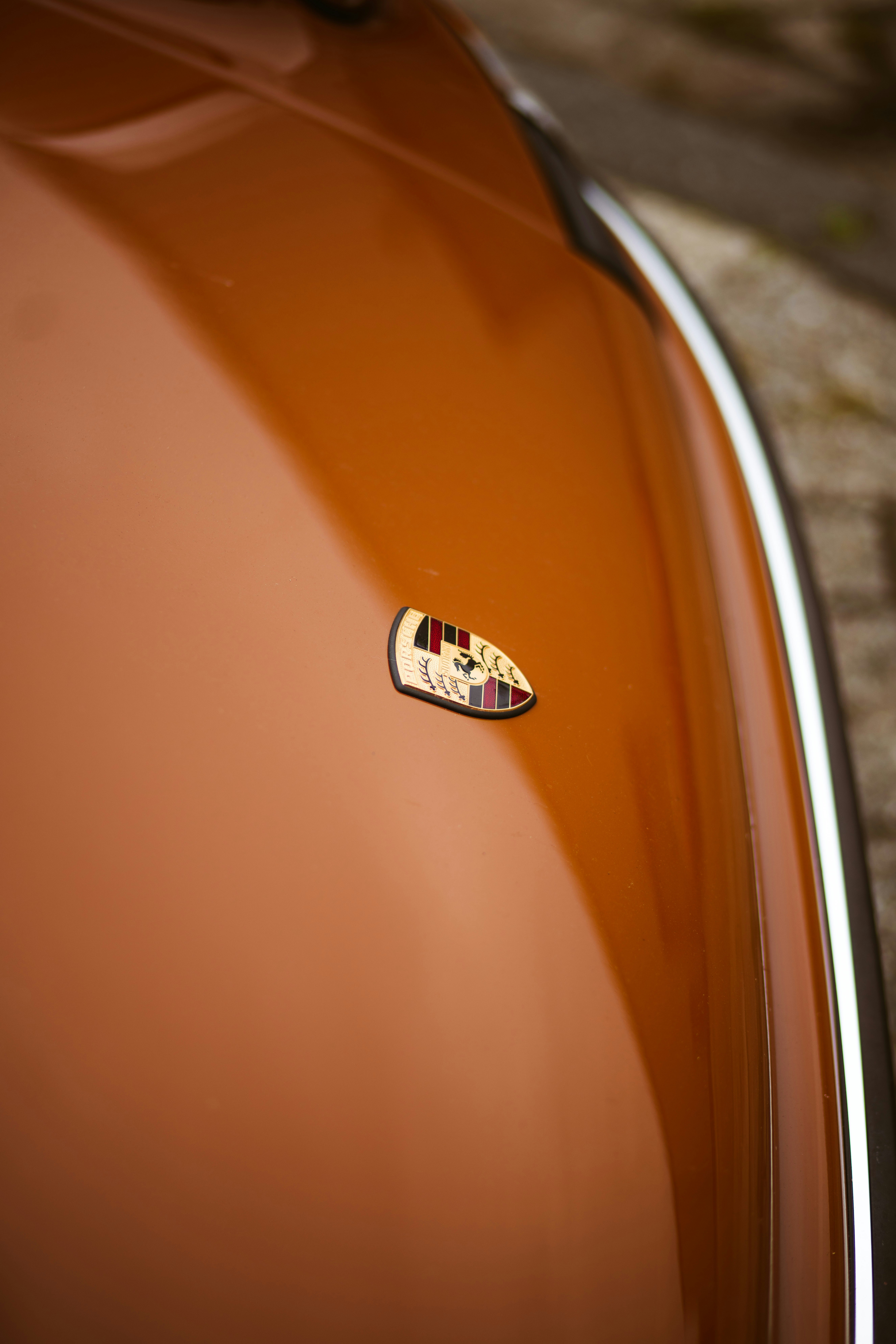 Emblem in Ember: Porsche Crest on a Glowing Orange Hood
