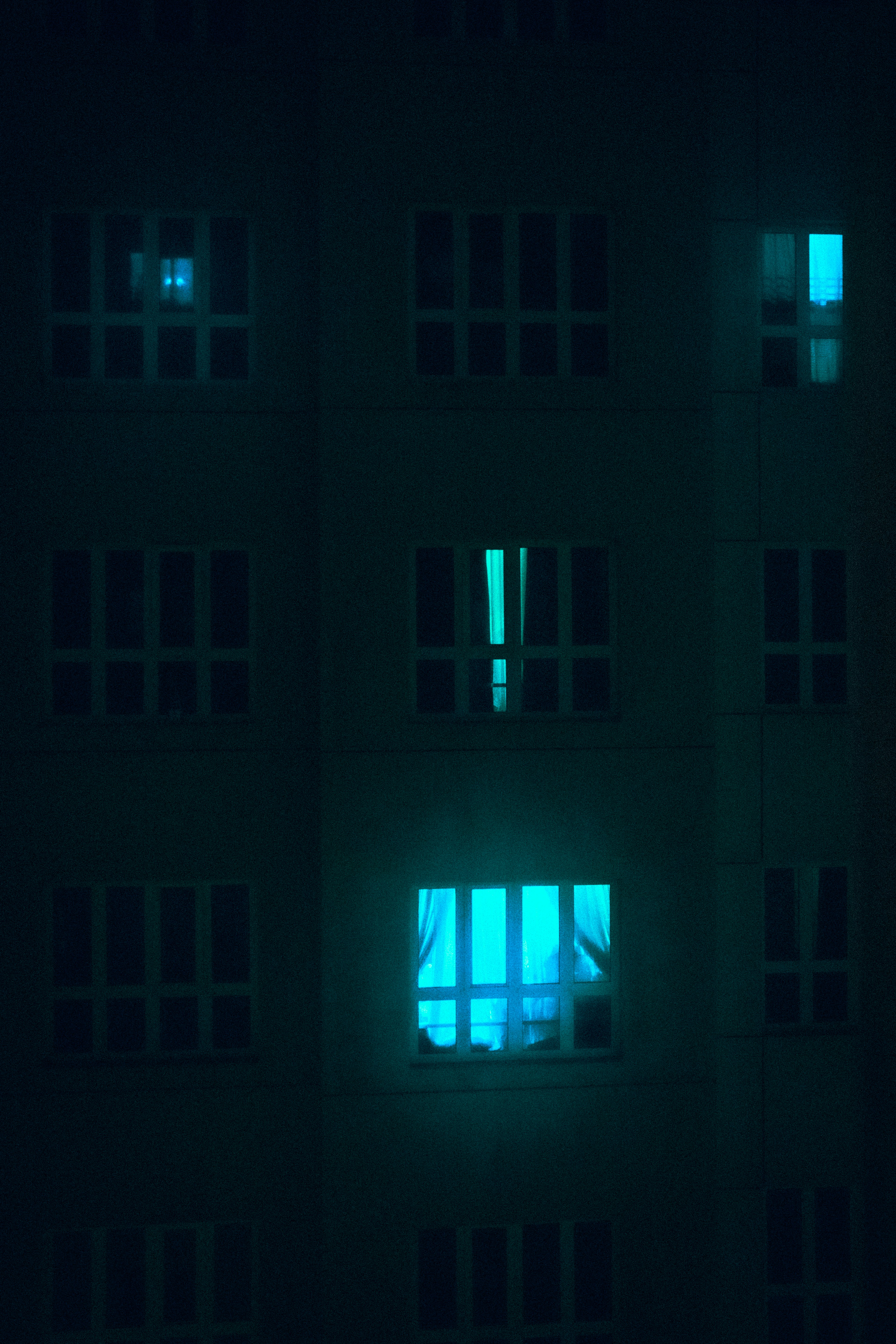 A building with several windows lit up in the dark photo – Free Home ...