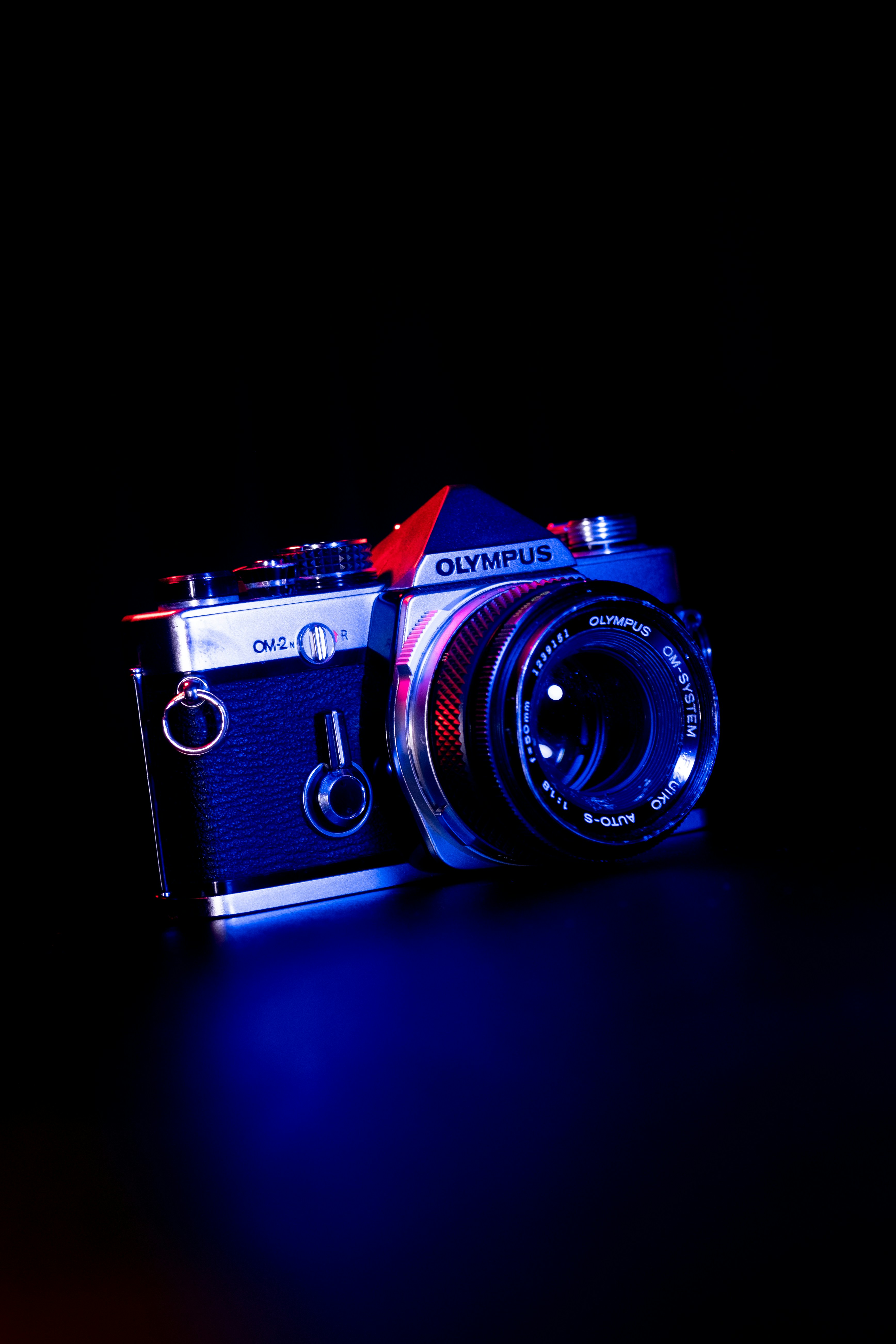 Classic Olympus camera with a sleek design illuminated by dramatic lighting against a dark backdrop.