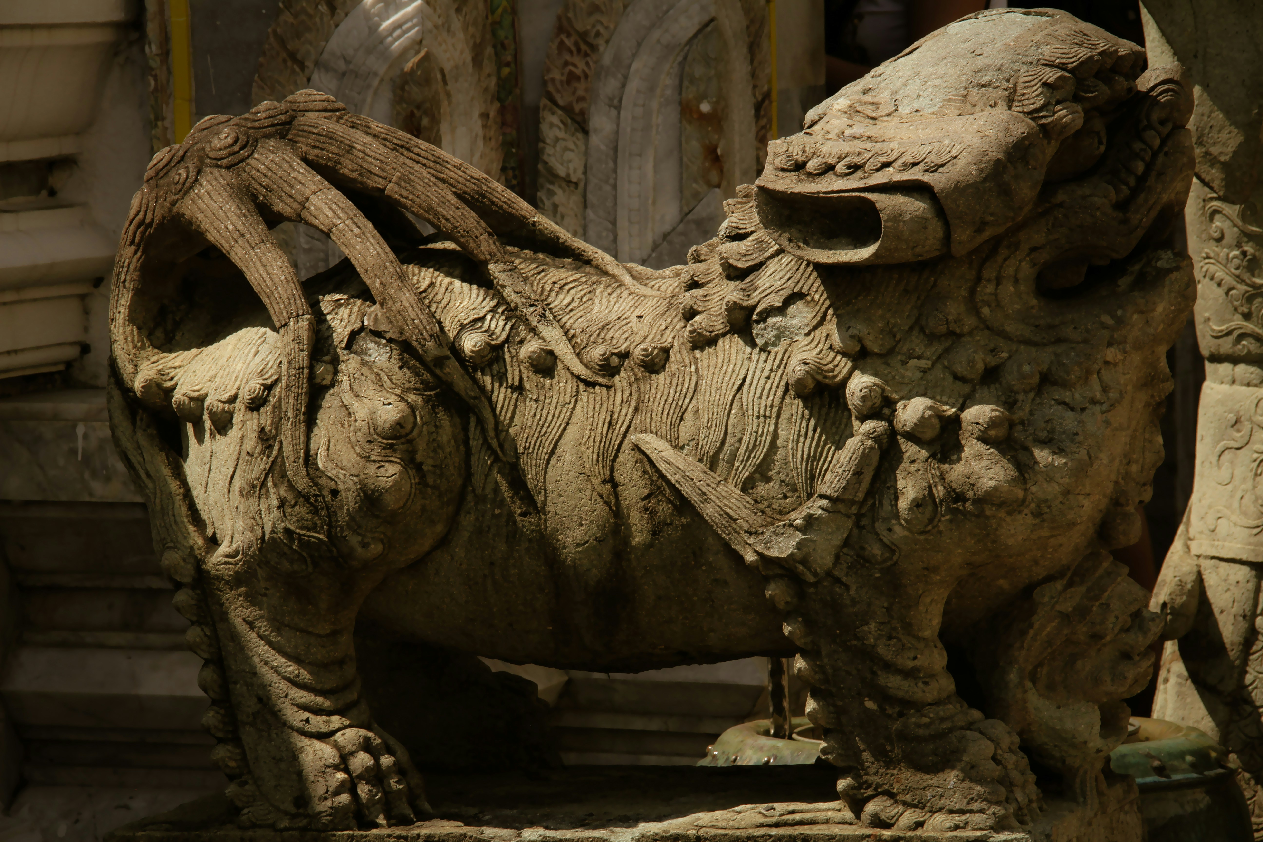 Stone Guardian: a weathered lion statue at rest amidst architectural shadows