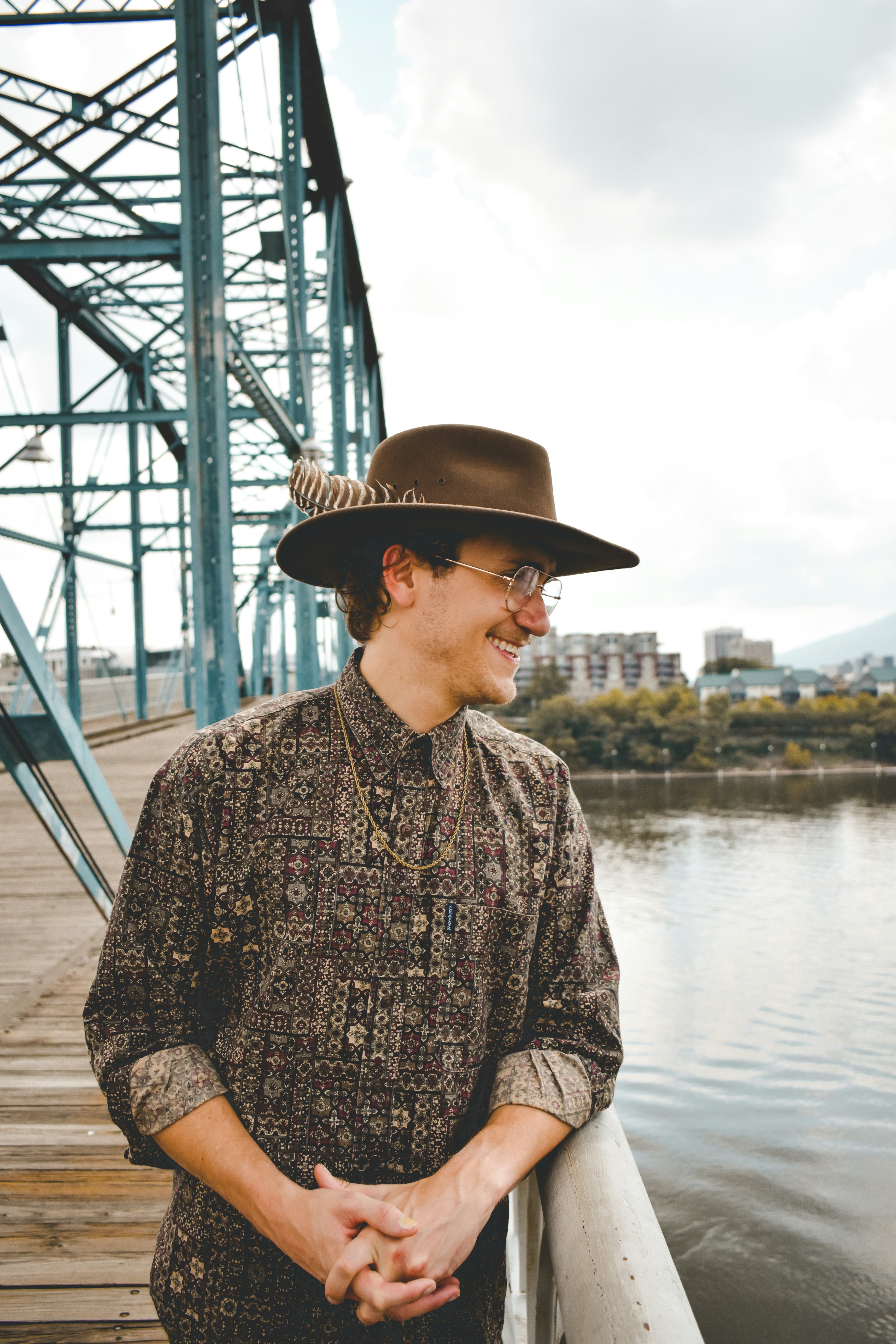 Feathered Hat Portrait Under a Riverfront Steel Bridge
