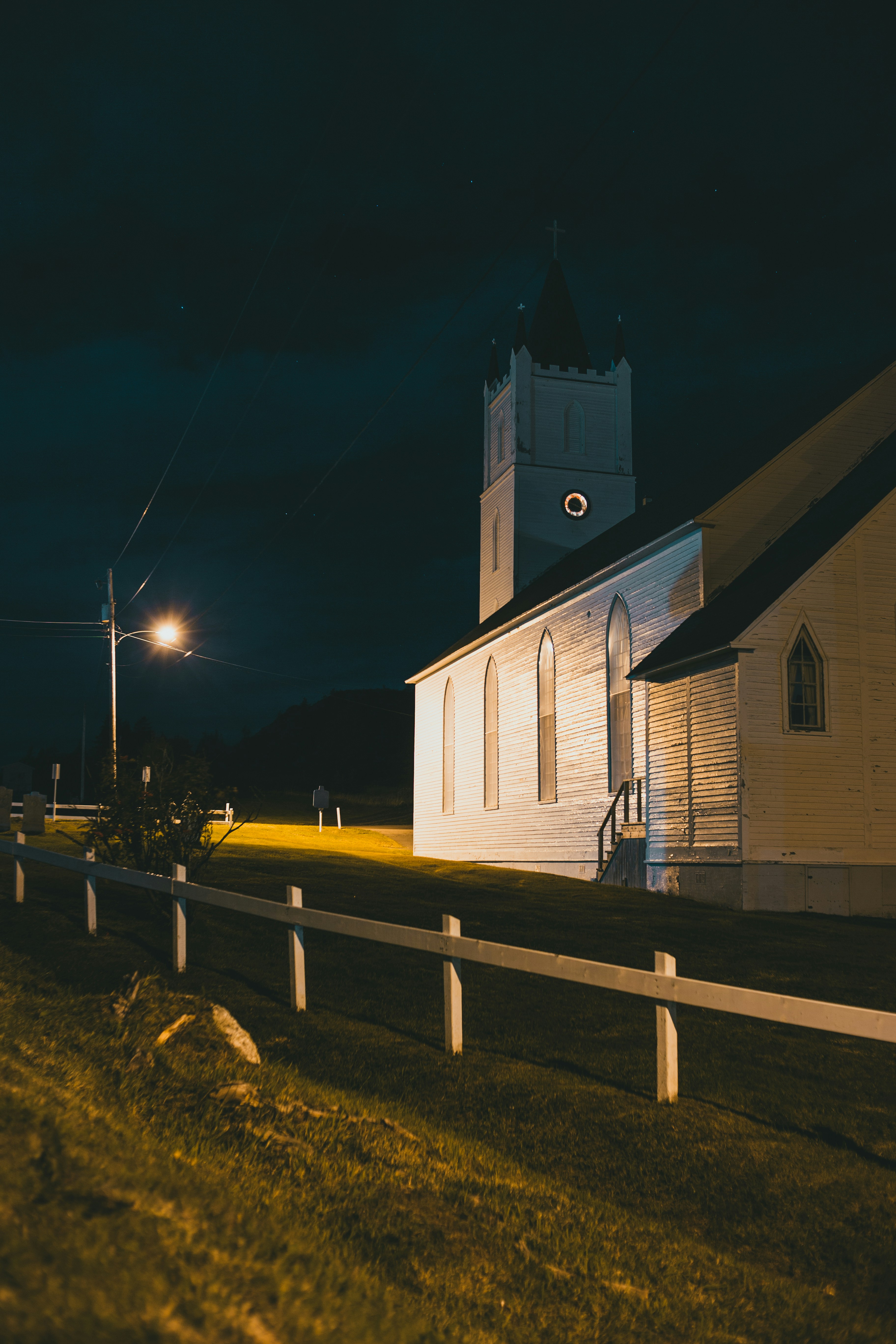 Historic church bathed in soft light under a starry night sky, with a glowing clock tower adding an air of serenity.