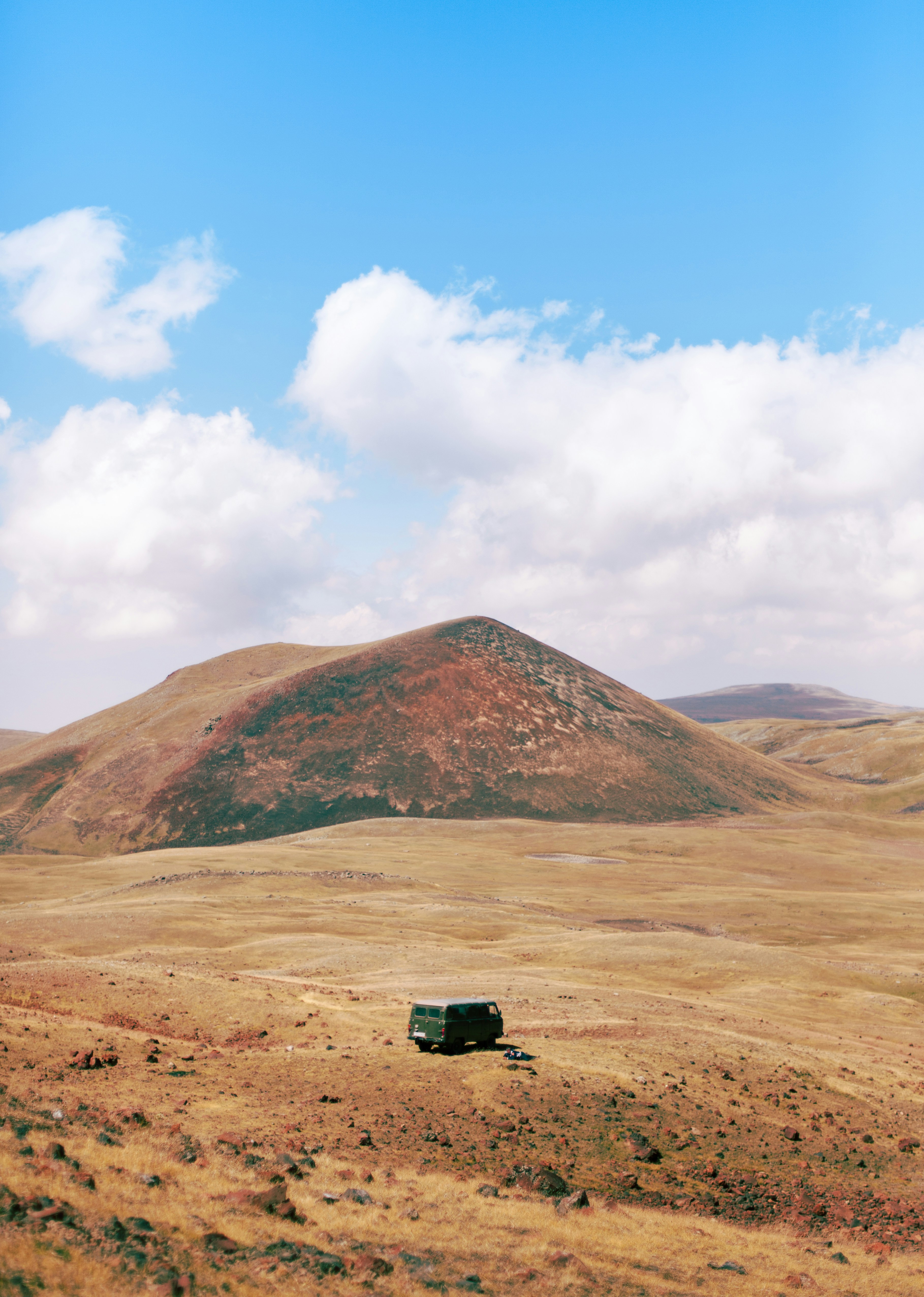 Green Van at the Foot of a Faded Hill under a Vast Sky