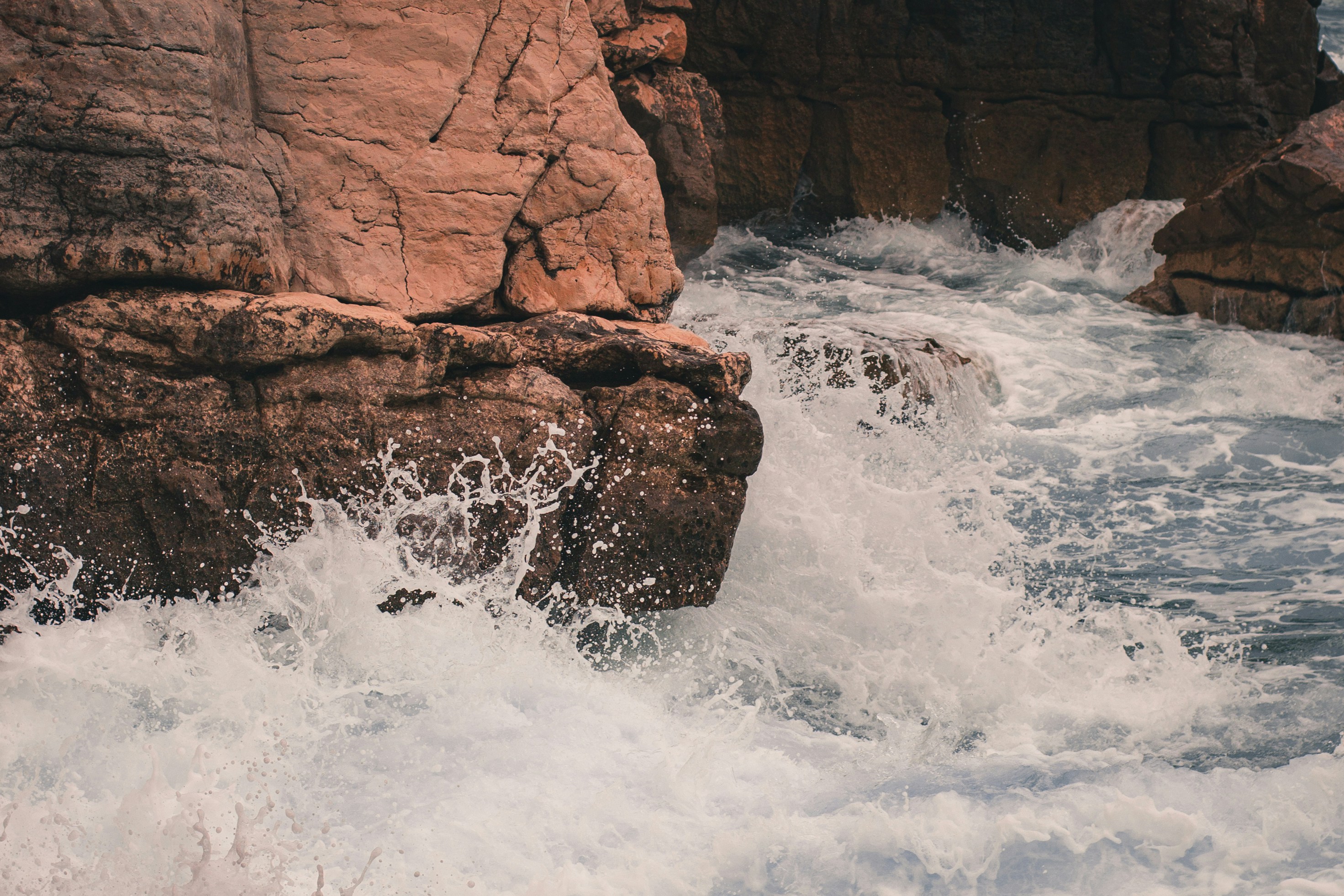 Dynamic waves crashing against rugged coastal rocks, capturing the relentless power of the ocean.