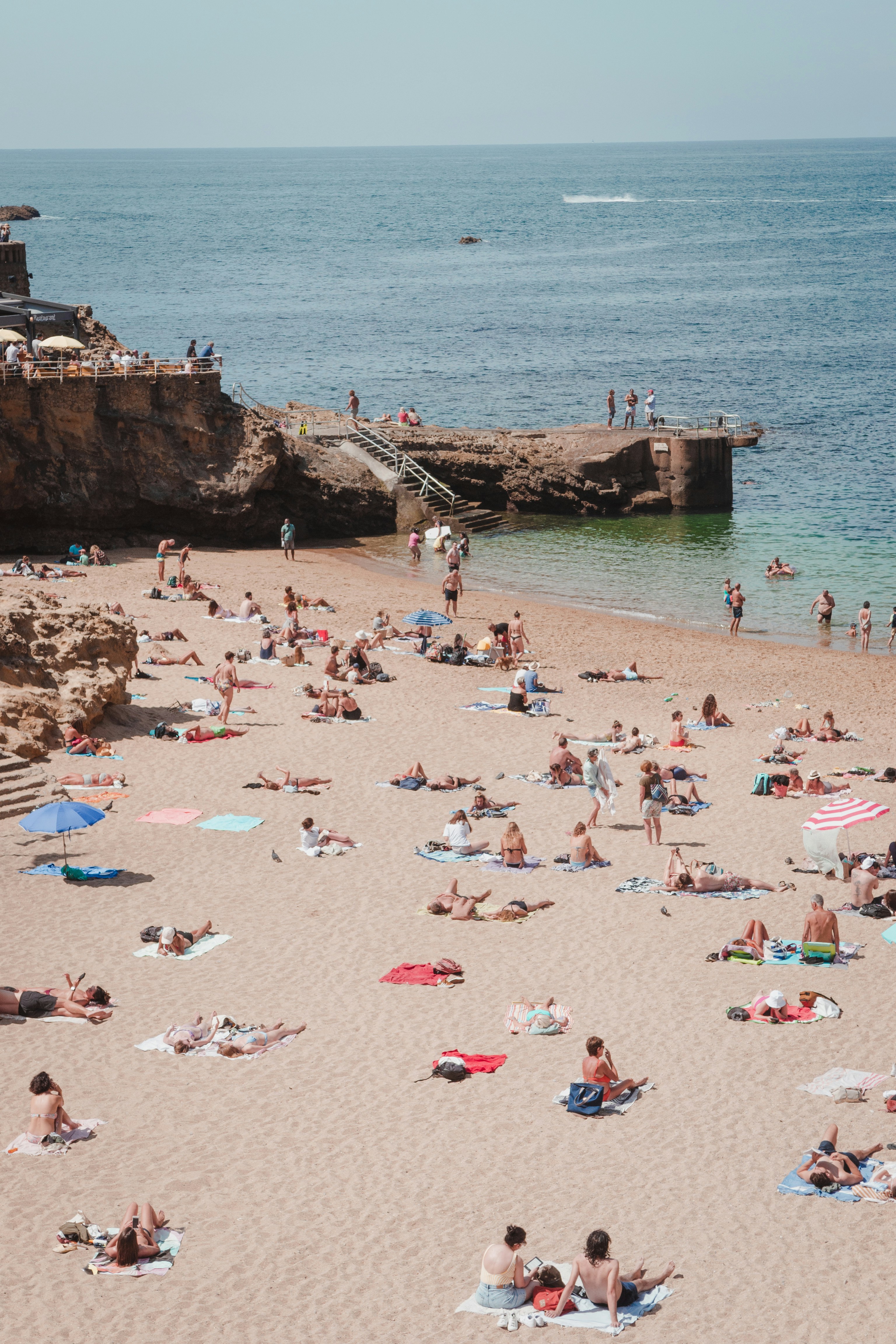 A crowded beach with people laying and standing on it photo – Free Sea ...