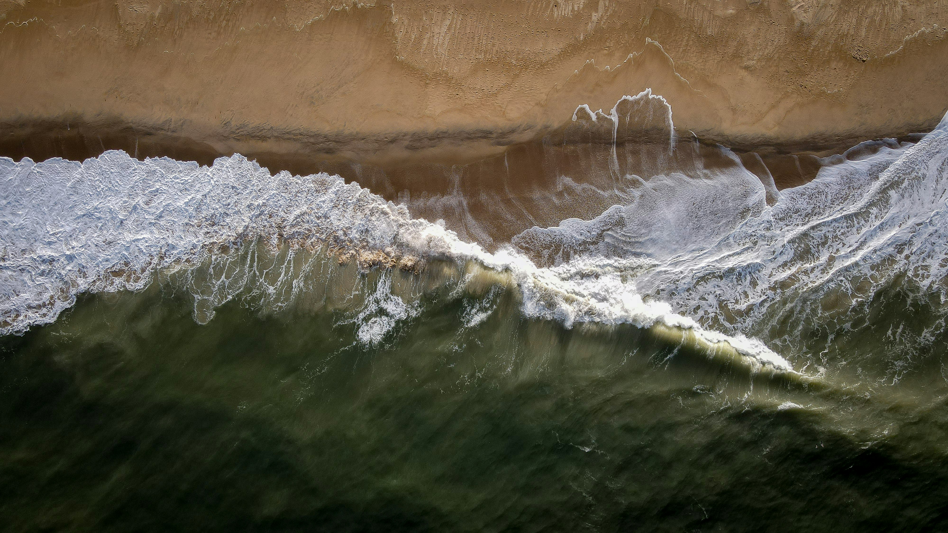 Above view of a wave breaking on the beach | an aerial view of a wave breaking on the beach