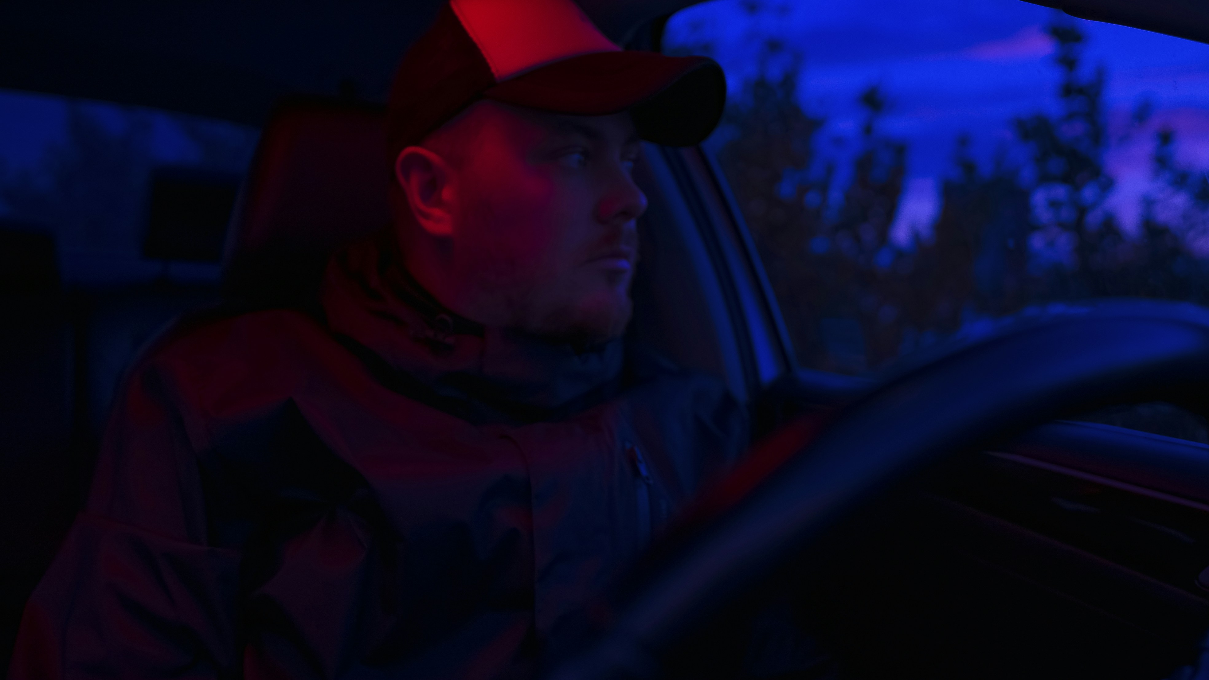 Neon Cabin Portrait: A Driver Bathed in Red and Blue