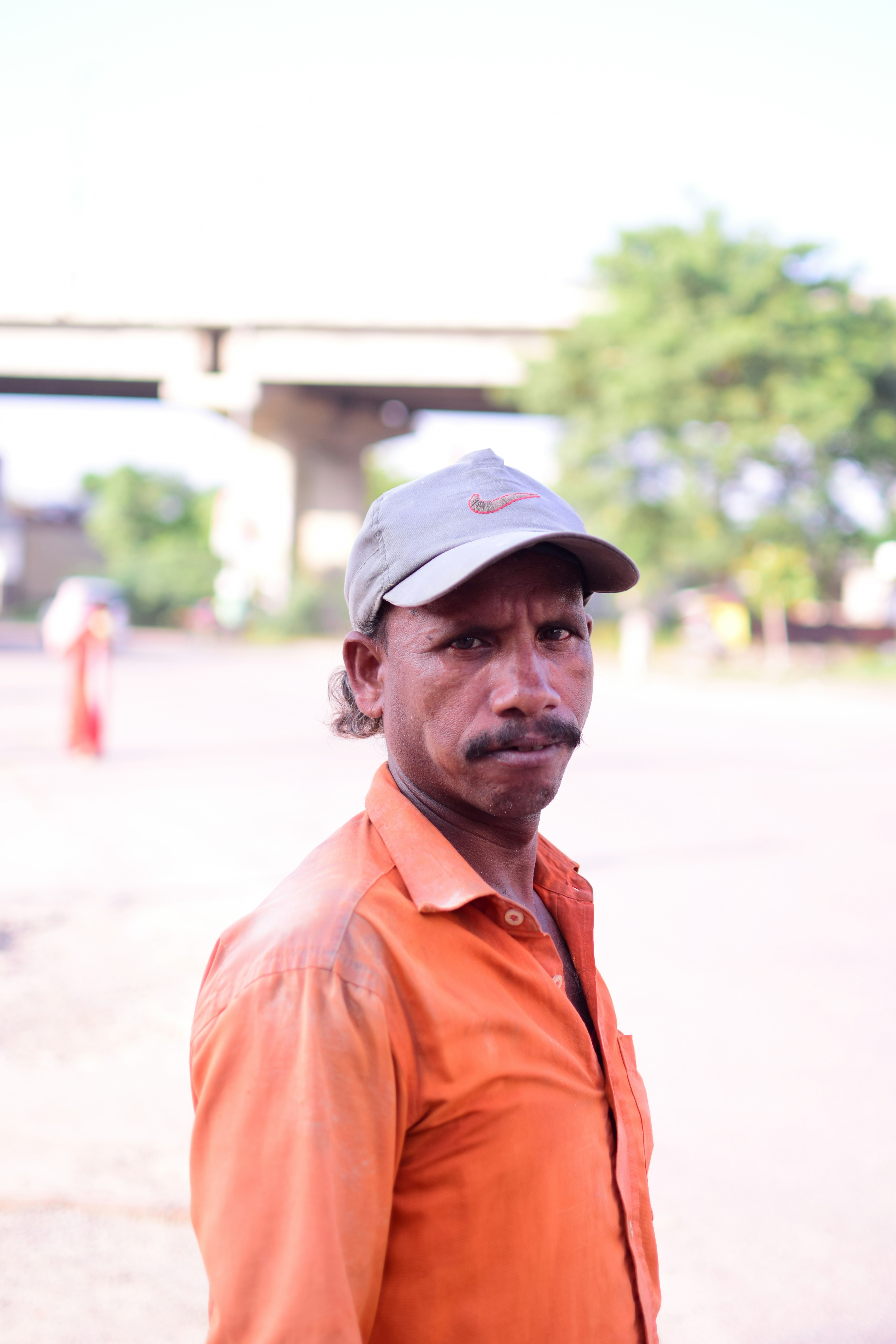 Portrait Under a Concrete Overpass: A Quiet Gaze in Orange