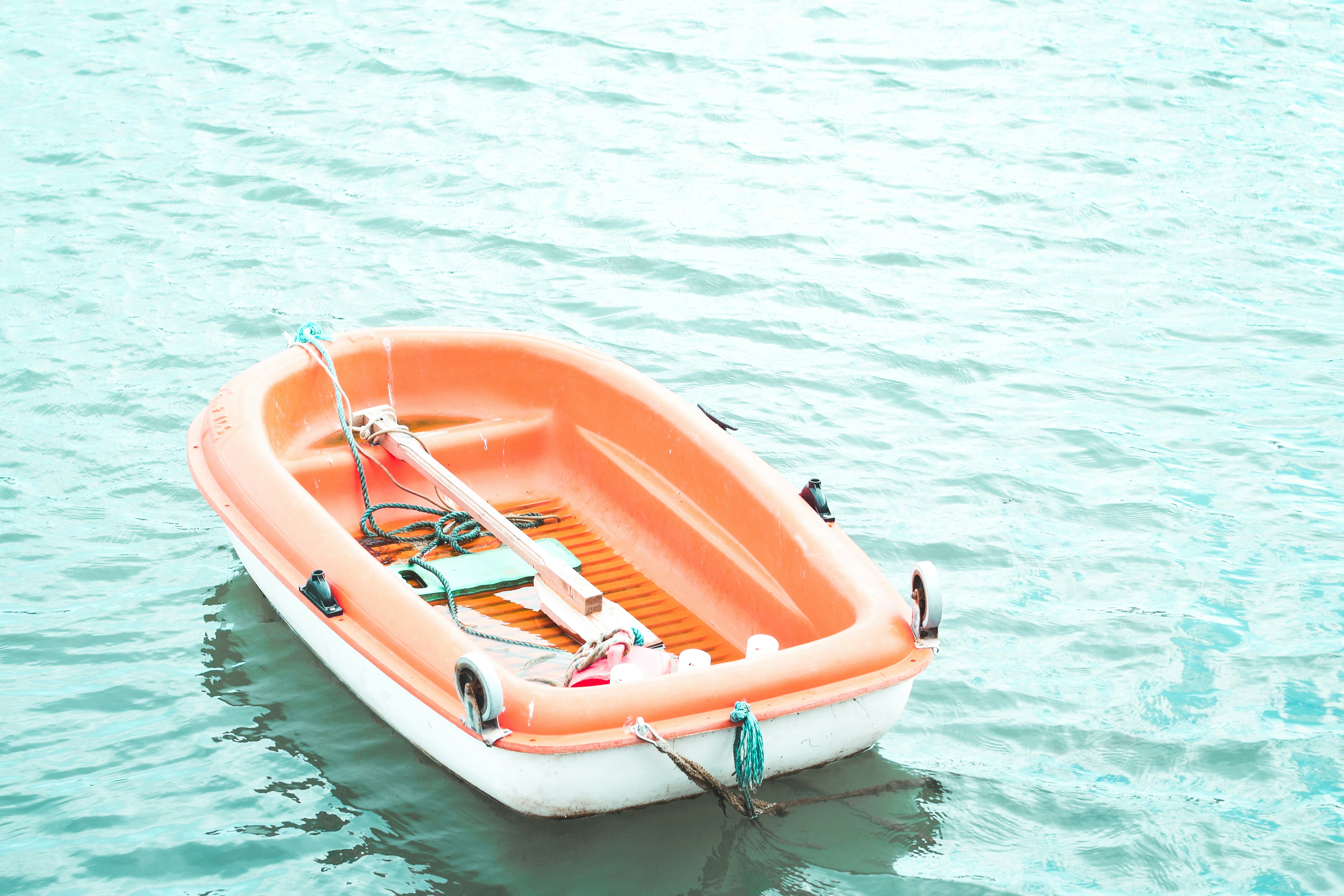 An orange and white boat gently floats on tranquil waters, surrounded by a soft, muted color palette. The scene evokes a sense of calm and solitude.