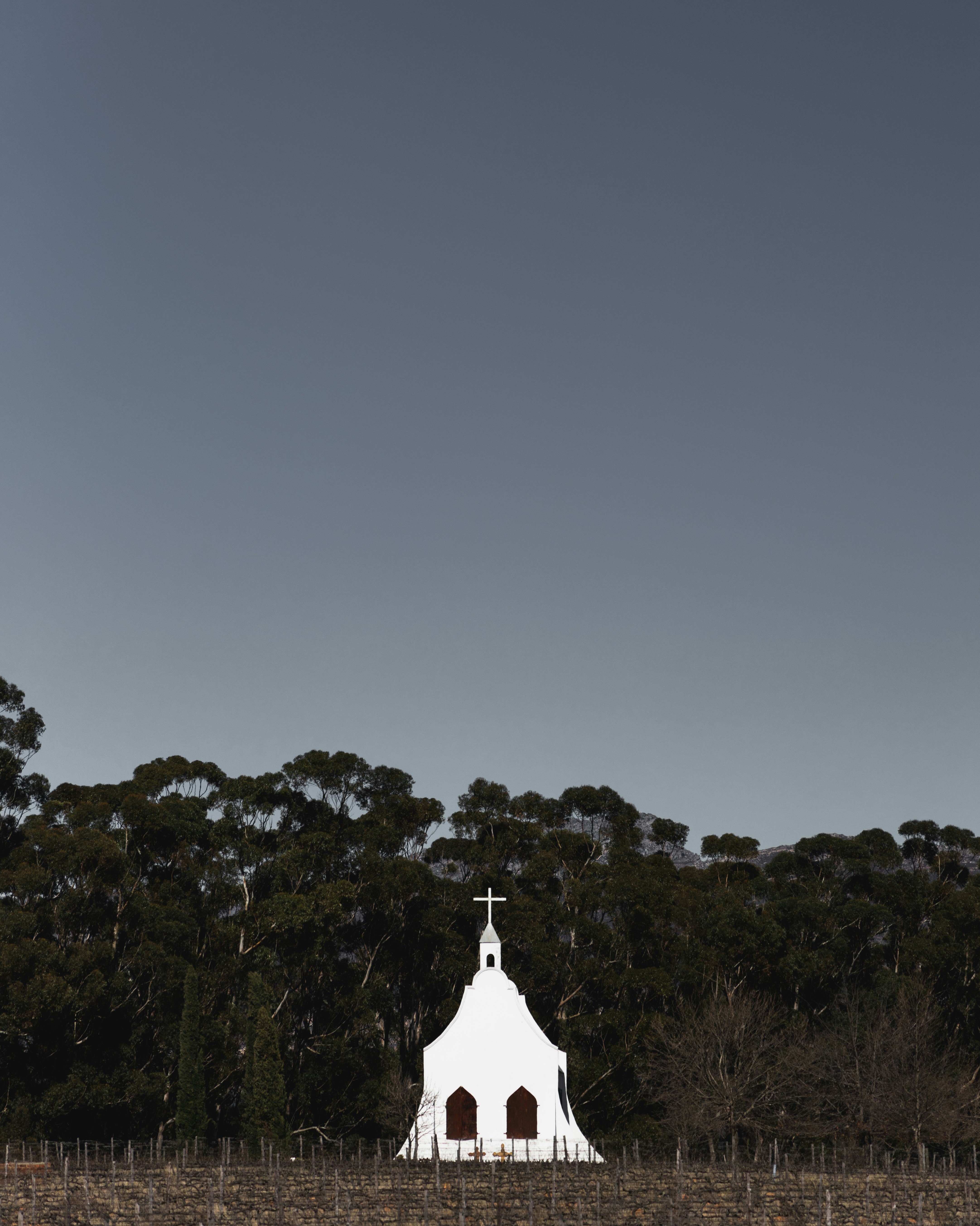Silhouette of a White Chapel Rising Above the Fence