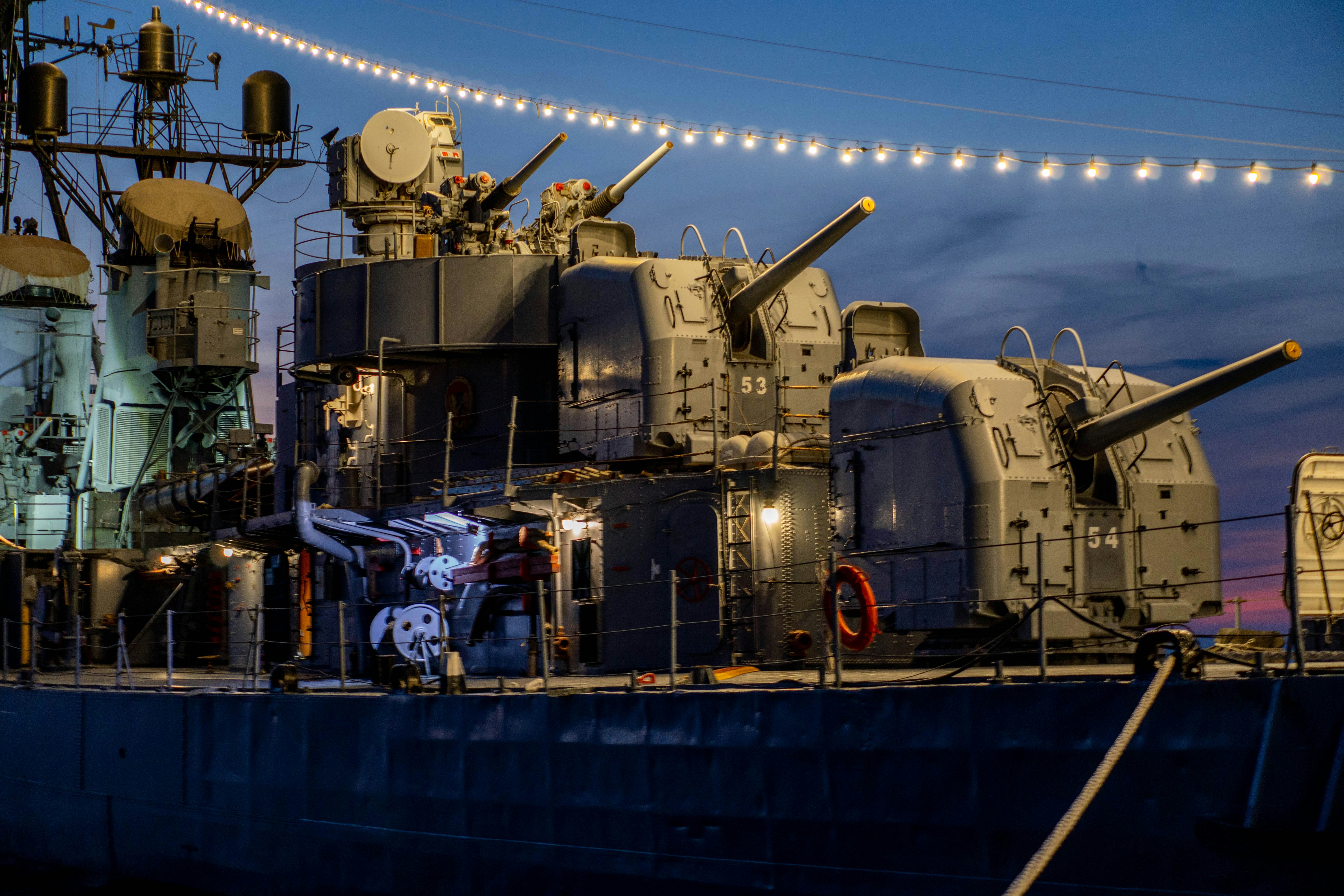 Dusk Sentinel: Harbor Lights Frame a Warship's Gunners