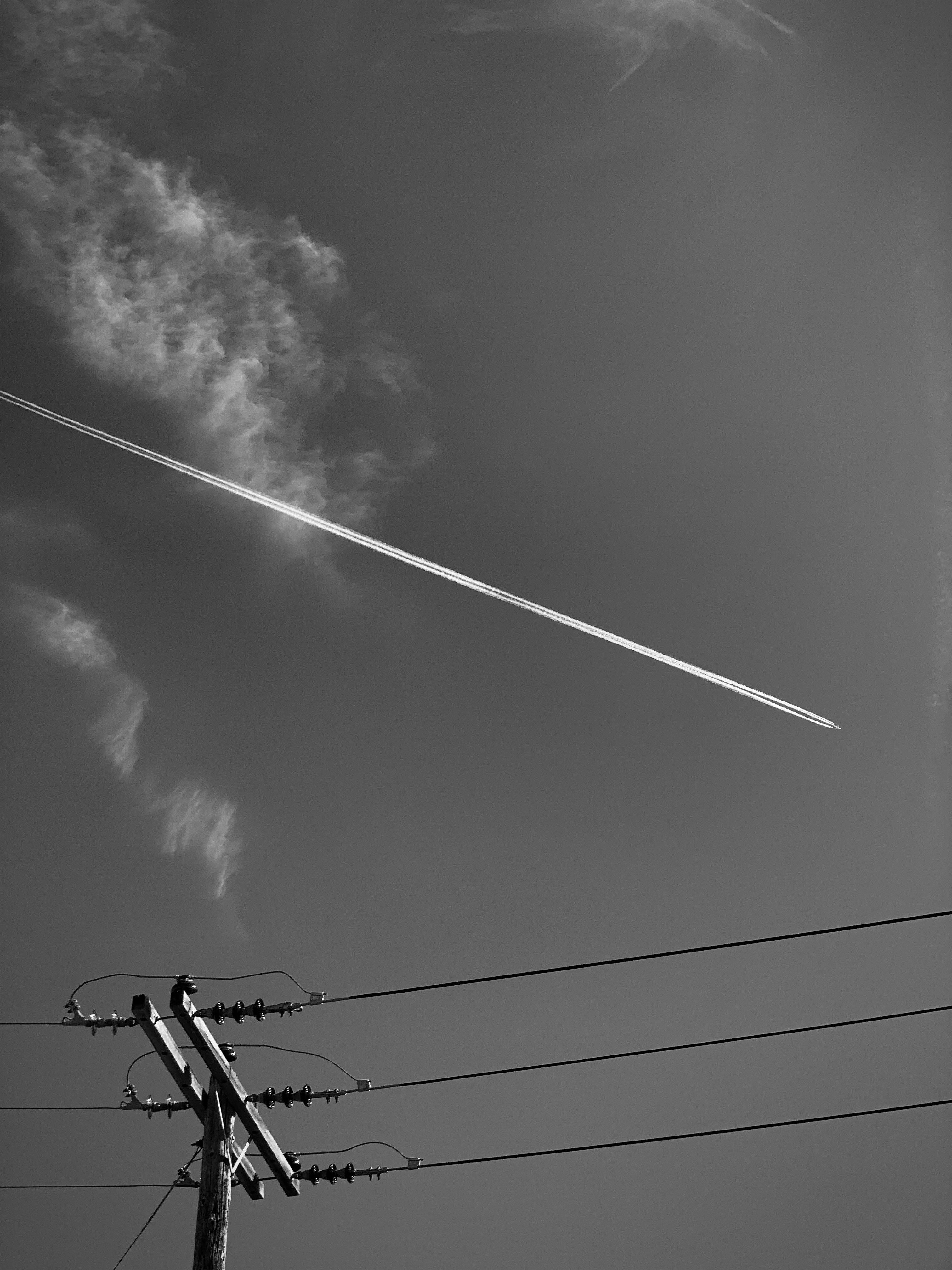 Monochrome Diagonal Contrail over a Quiet Power Grid