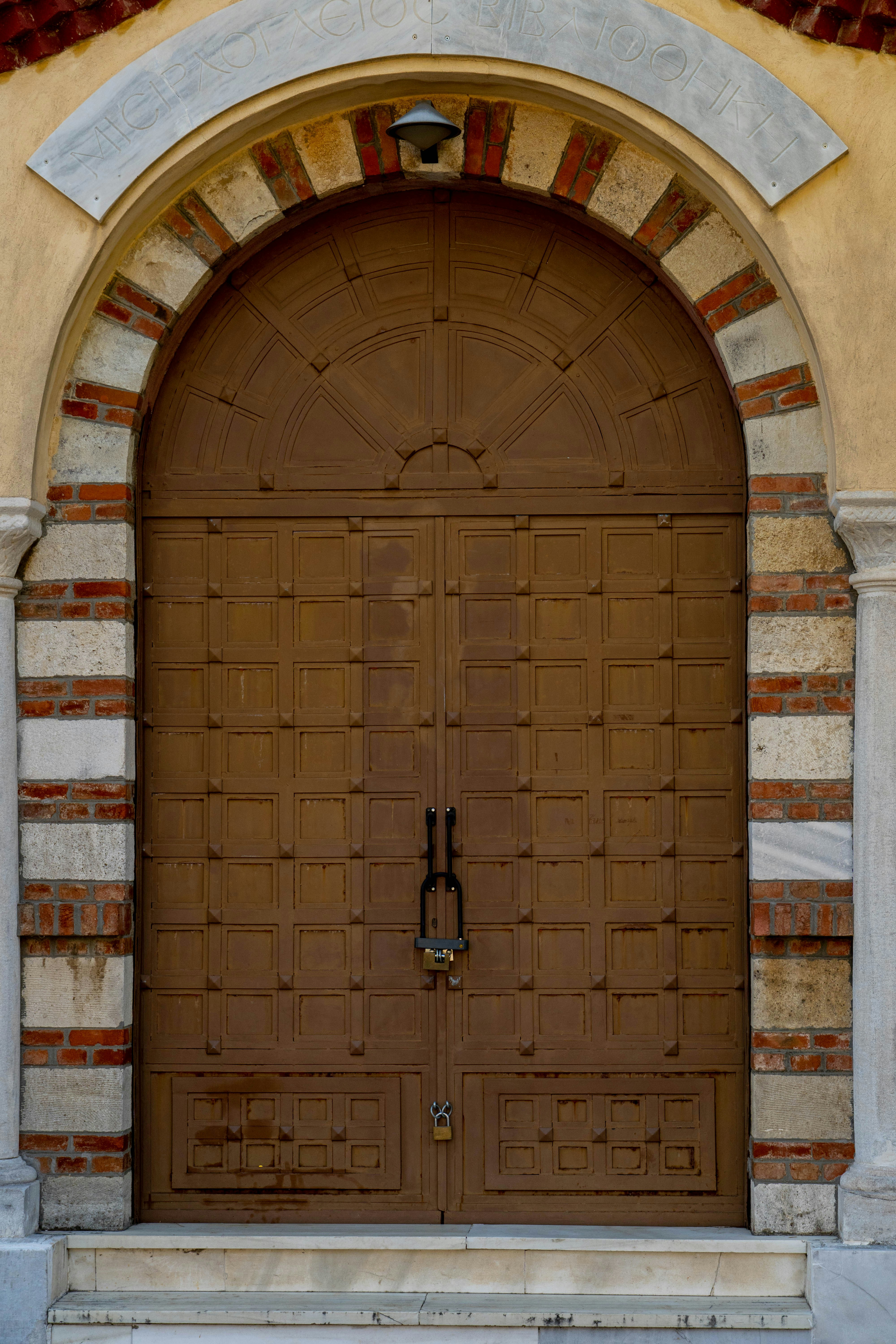 Intricately designed wooden door with a padlock, framed by ornate stonework and brick, showcasing architectural elegance.