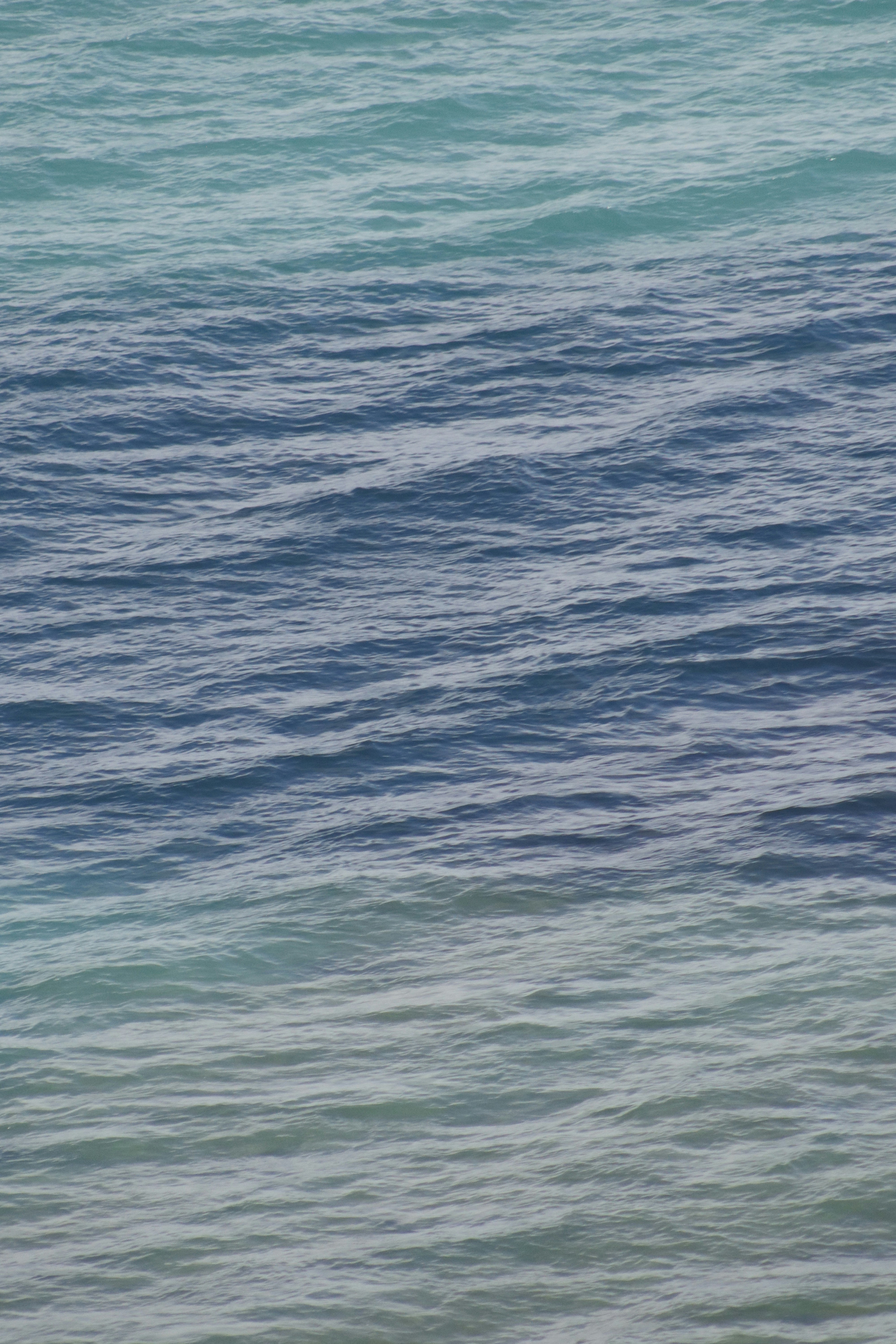 Dynamic layers of blue and turquoise water create a mesmerizing pattern, showcasing the ocean's natural beauty.