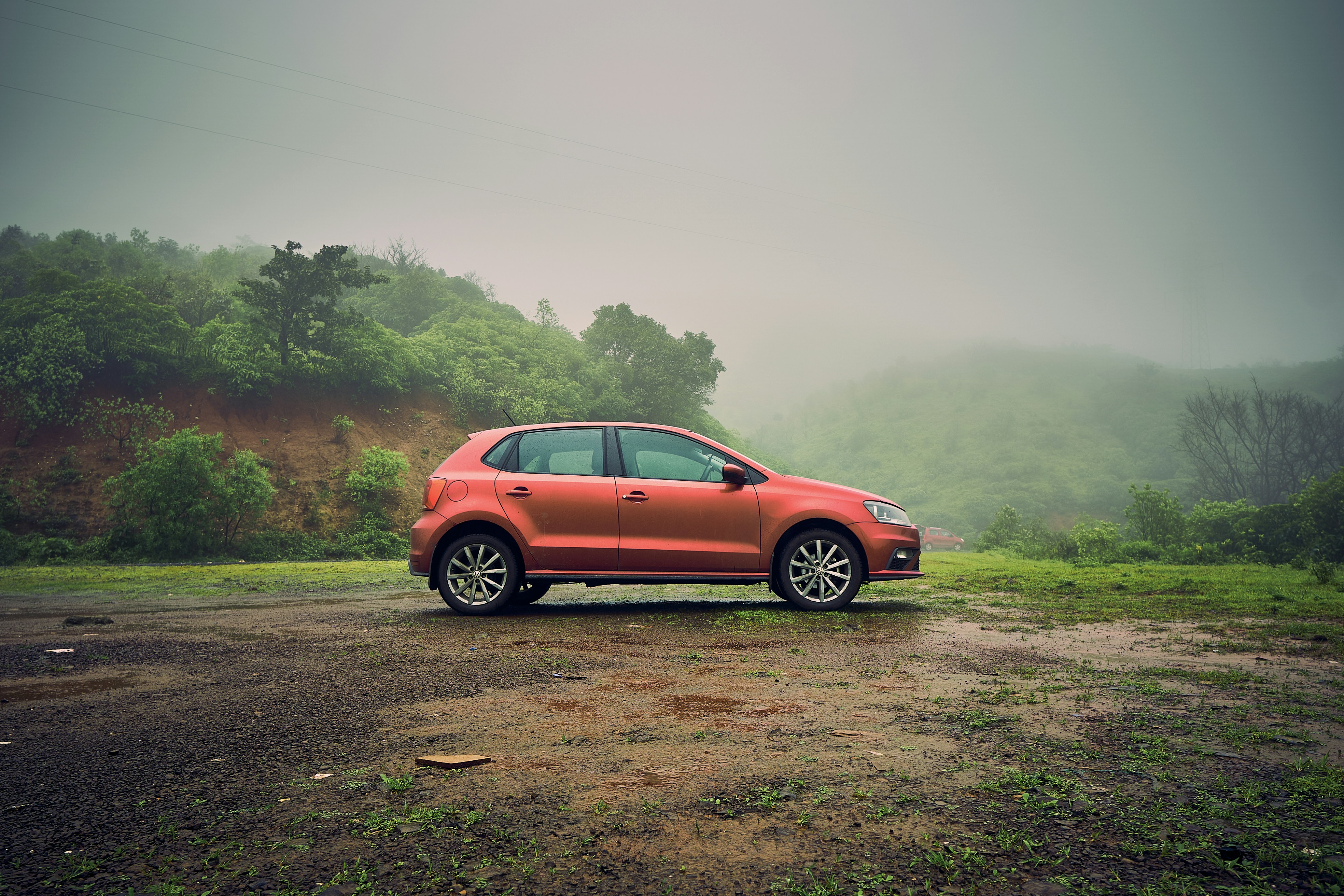 Crimson SUV Amid Mist and Verdant Hills