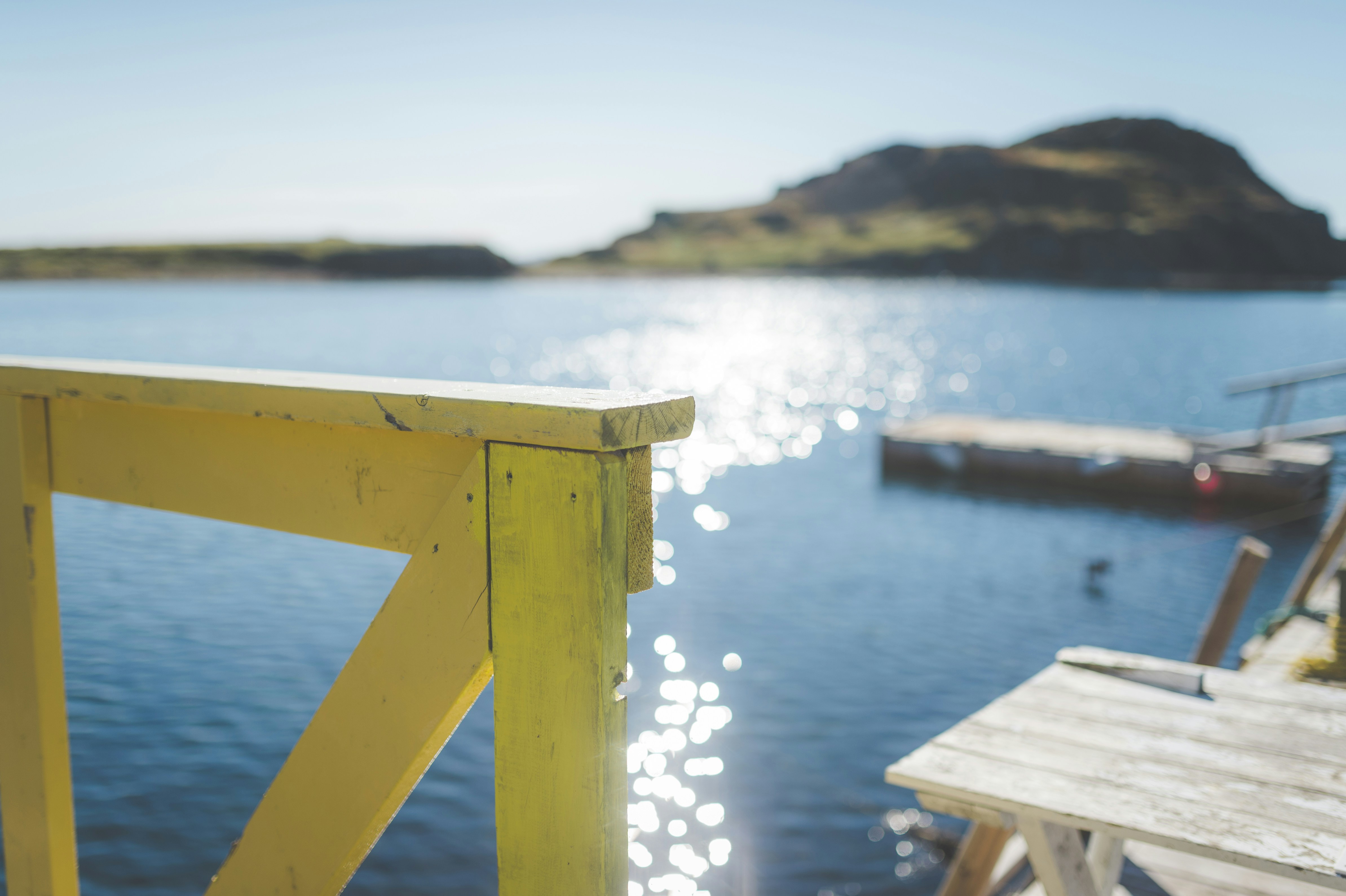 Sunlit Yellow Railing Framing a Sparkling Lakeside Panorama