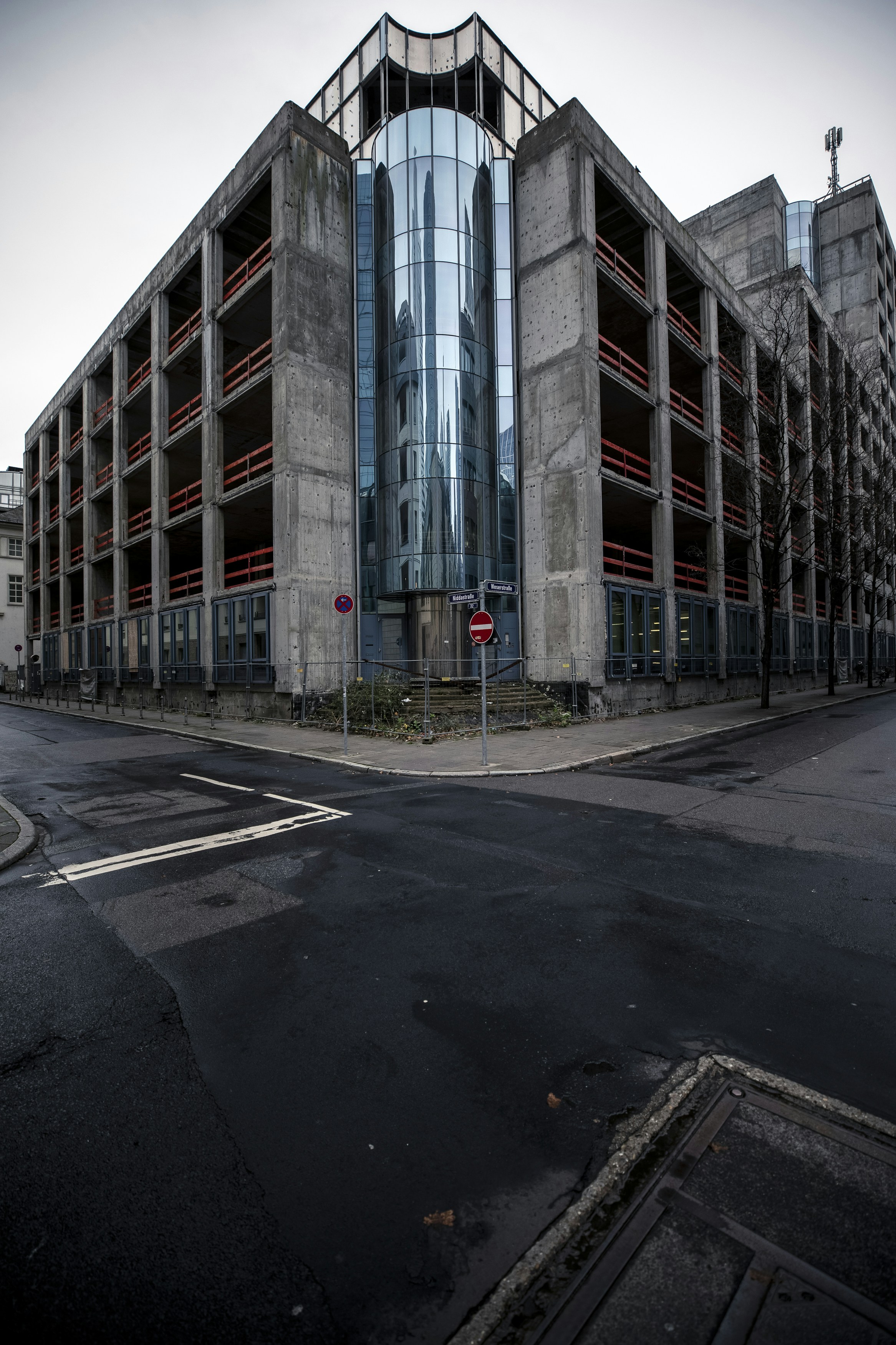 Glass Spine Rising from Brutalist Geometry at a Street Corner