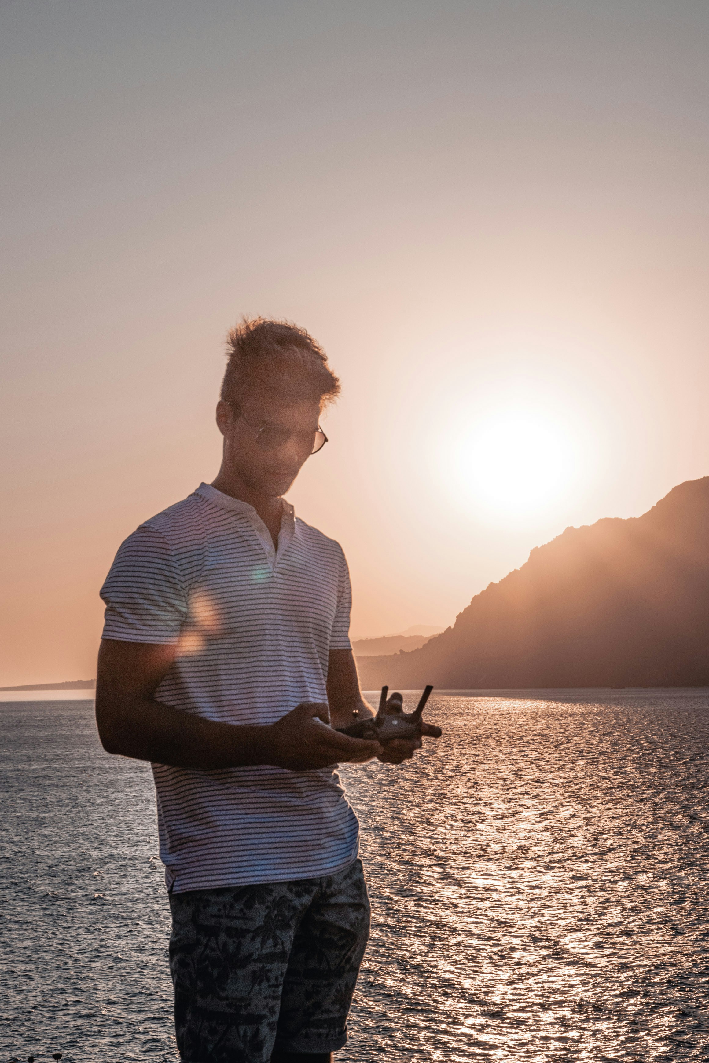 Evening at the Horizon: Man with Remote by the Sunlit Sea