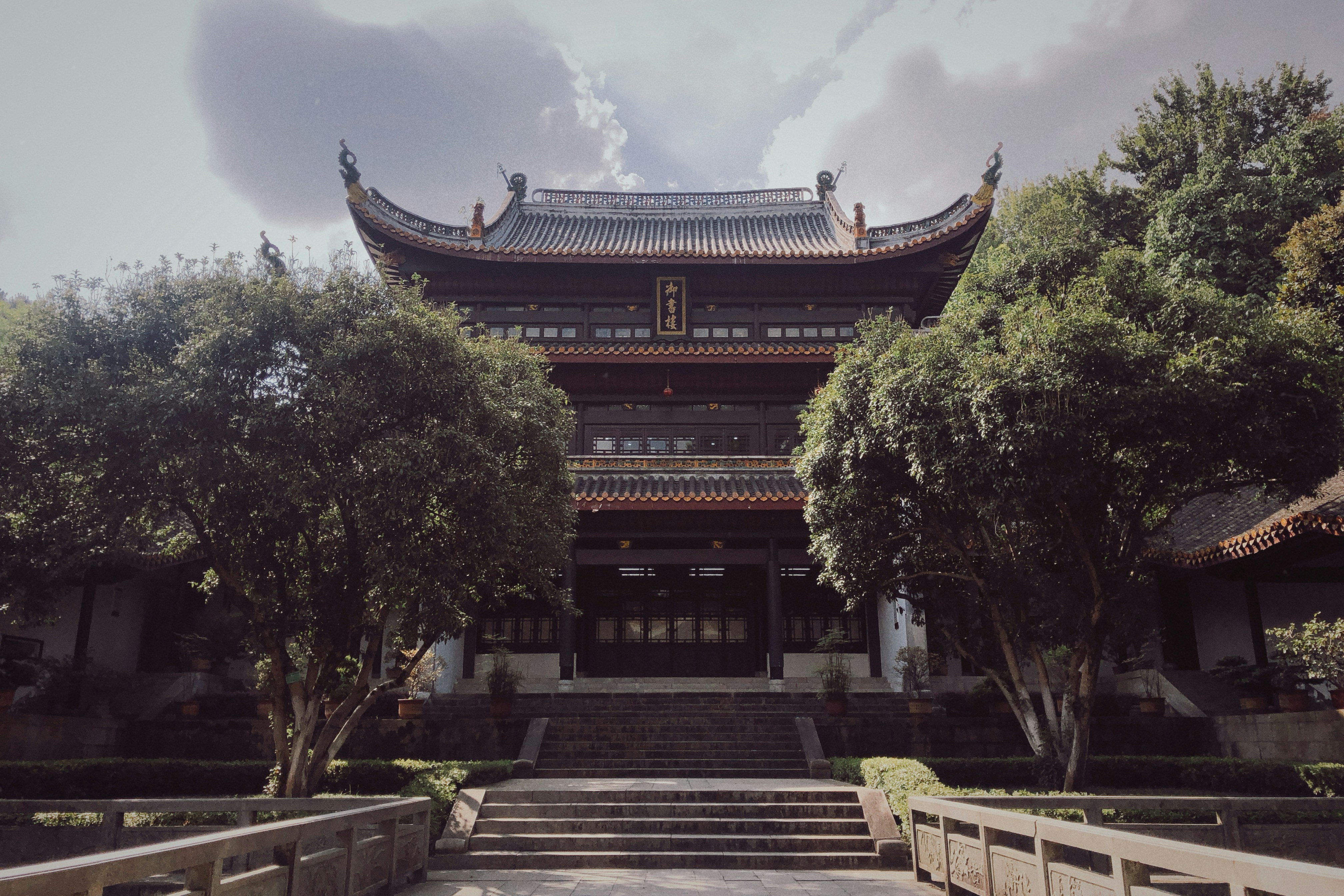 Traditional Asian architecture framed by lush greenery, showcasing a serene temple entrance with intricate details.