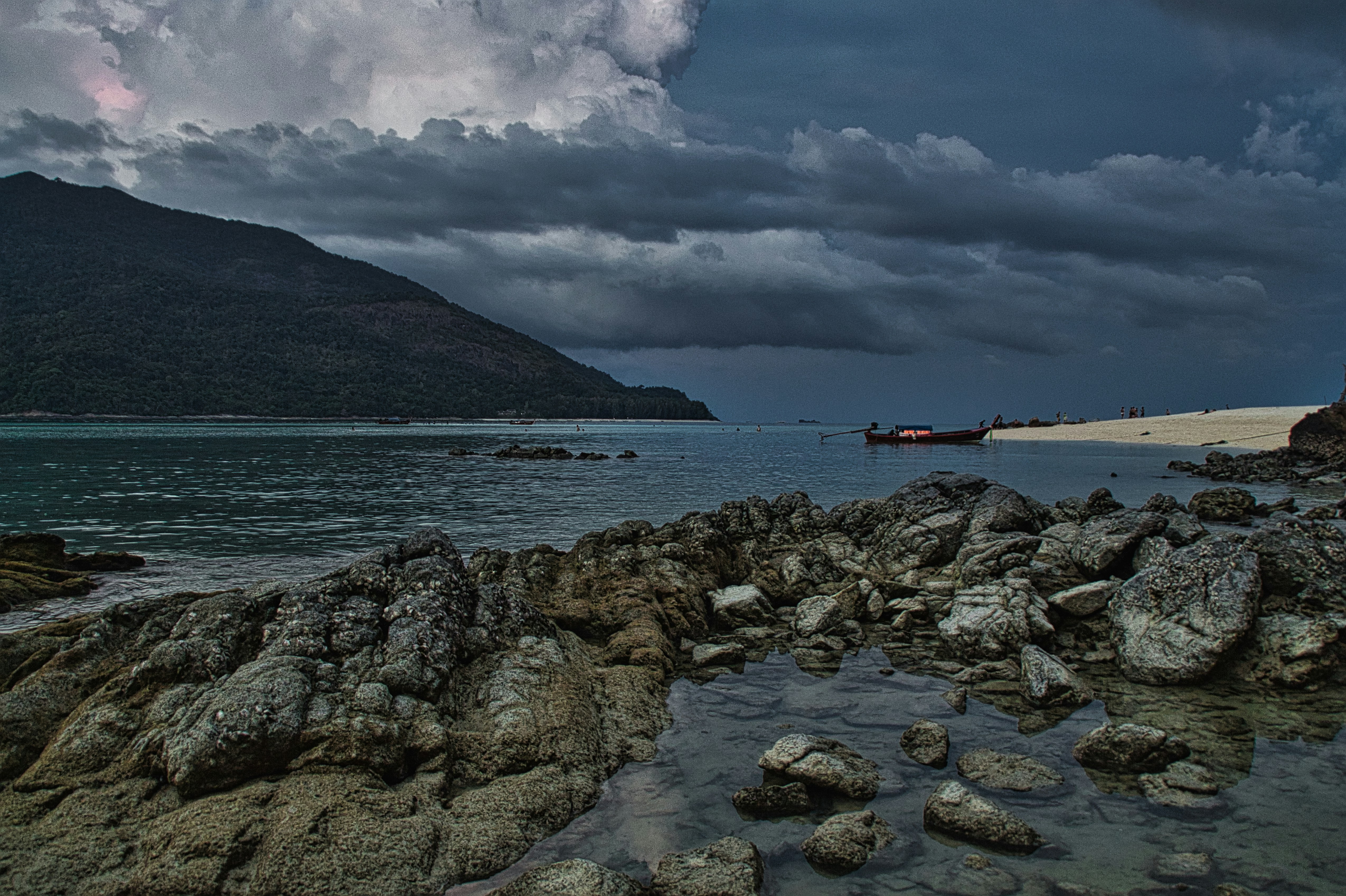 Boat at the Break: A Rocky Coastal Verge Beneath Looming Clouds
