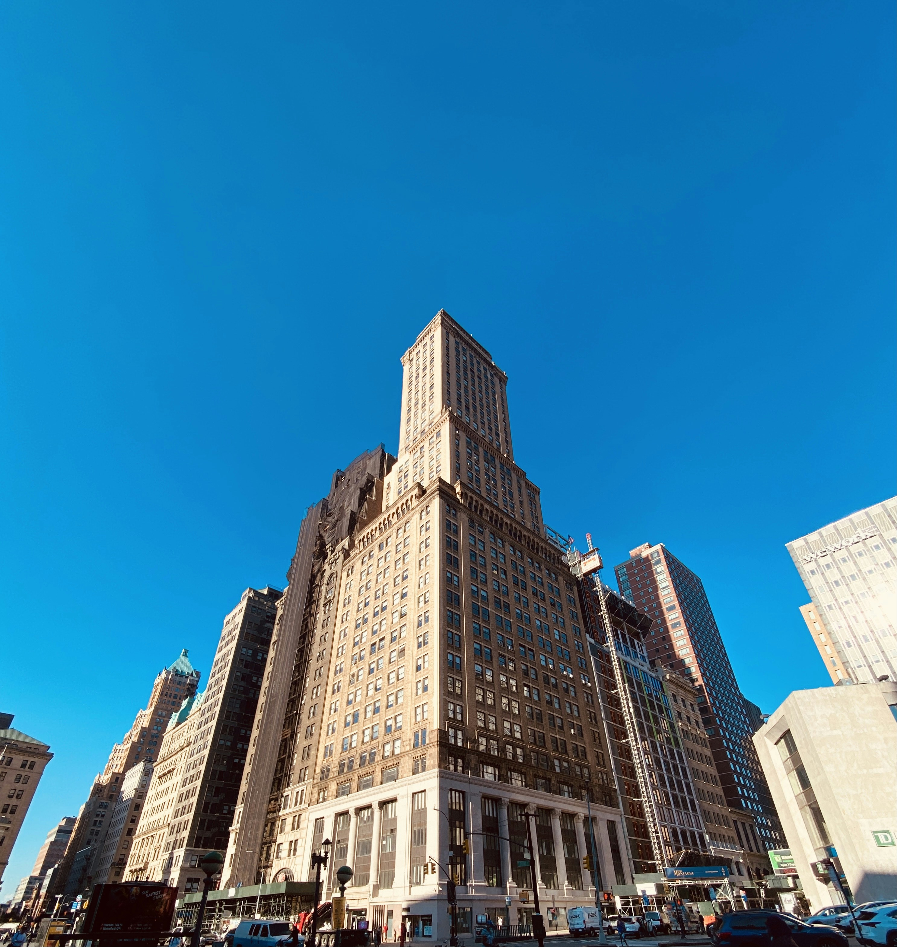 A towering historical building juxtaposed against modern skyscrapers under a clear blue sky.