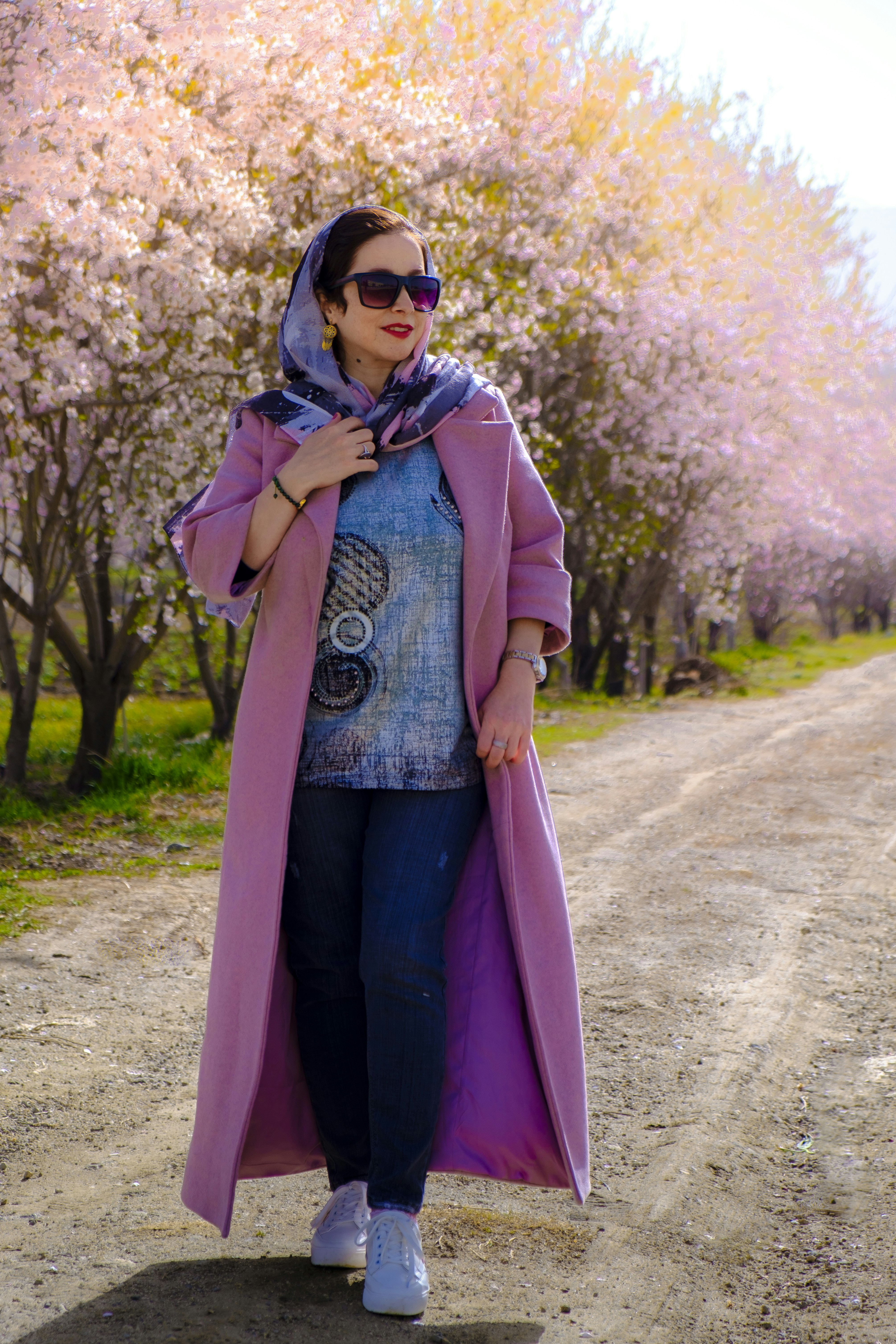 a woman wearing a purple coat and sunglasses