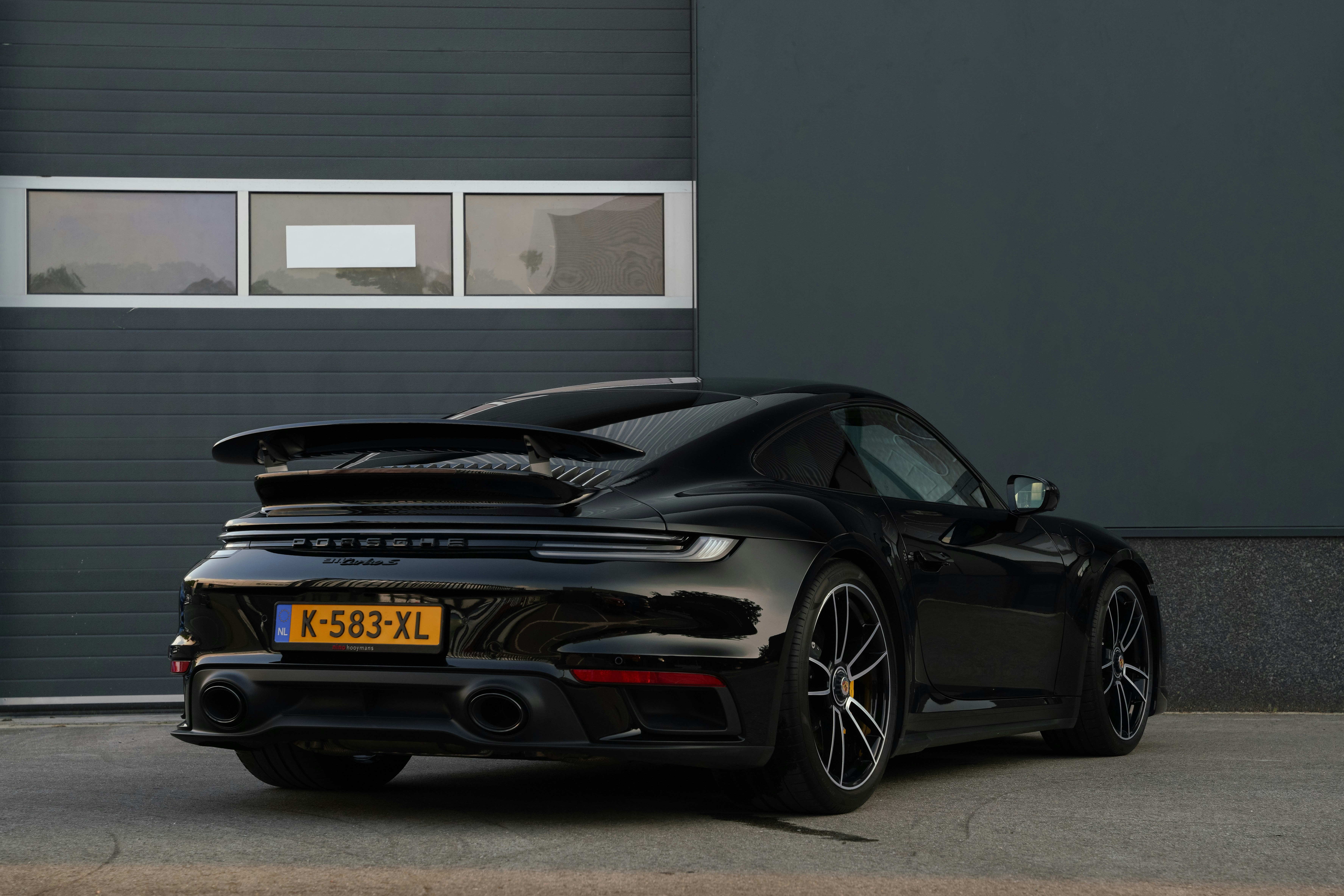Sleek black sports car parked in front of a modern gray building.