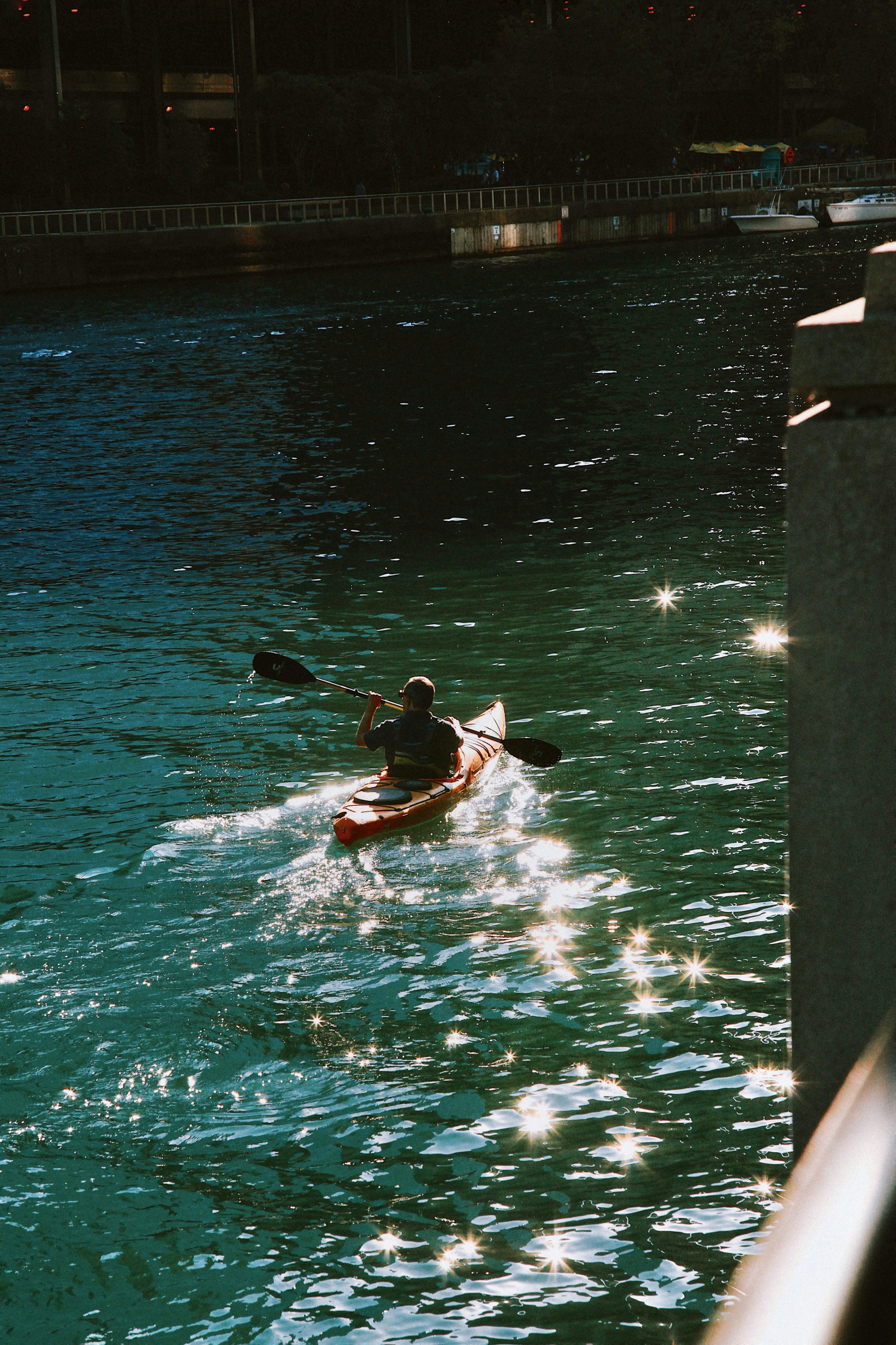 Emerald Wake: Kayaker Carves a Quiet Arc Under City Lights