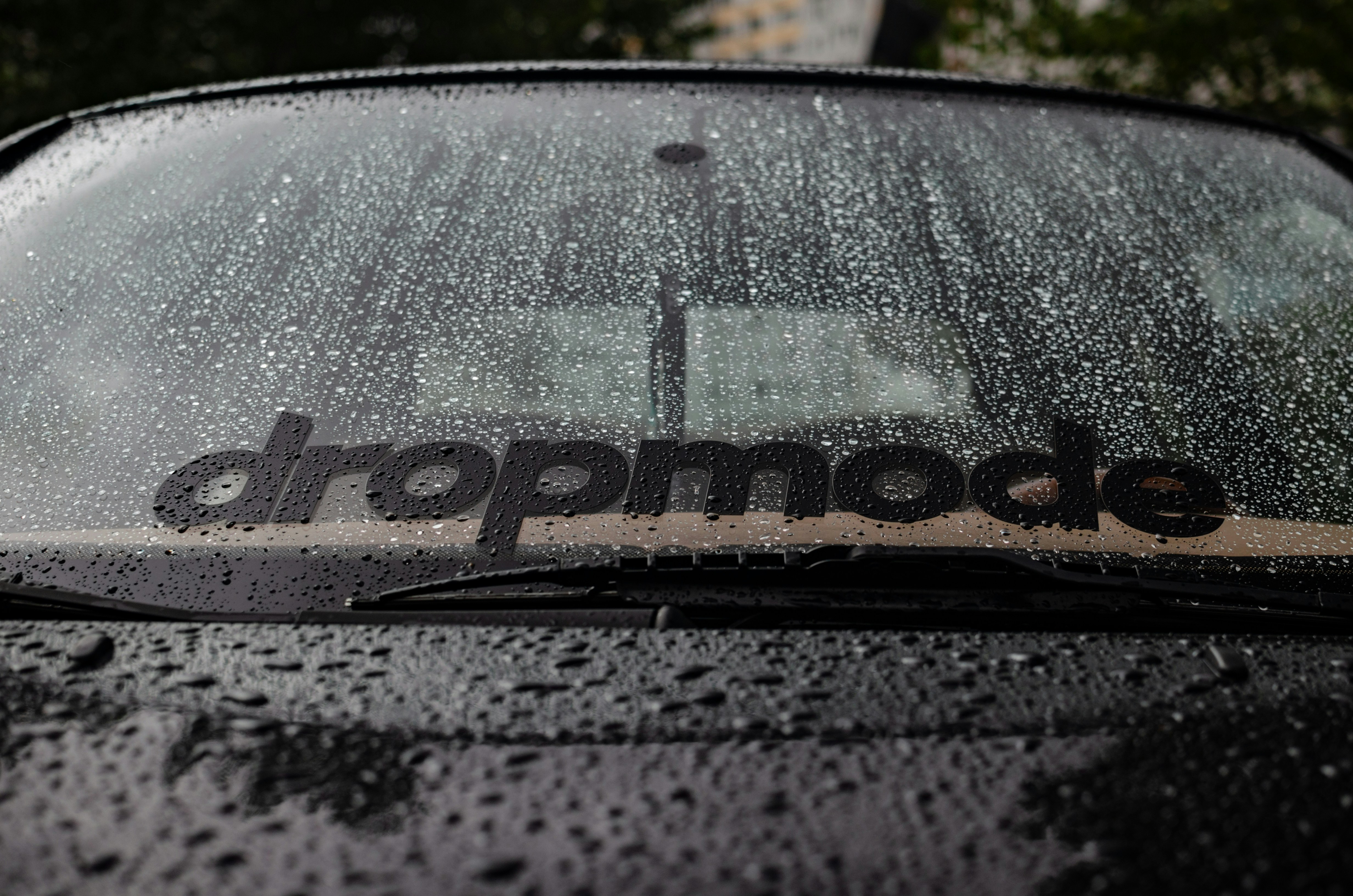 Rain-Glass Branding: The Dropmode Emblem on a Wet Hatchback