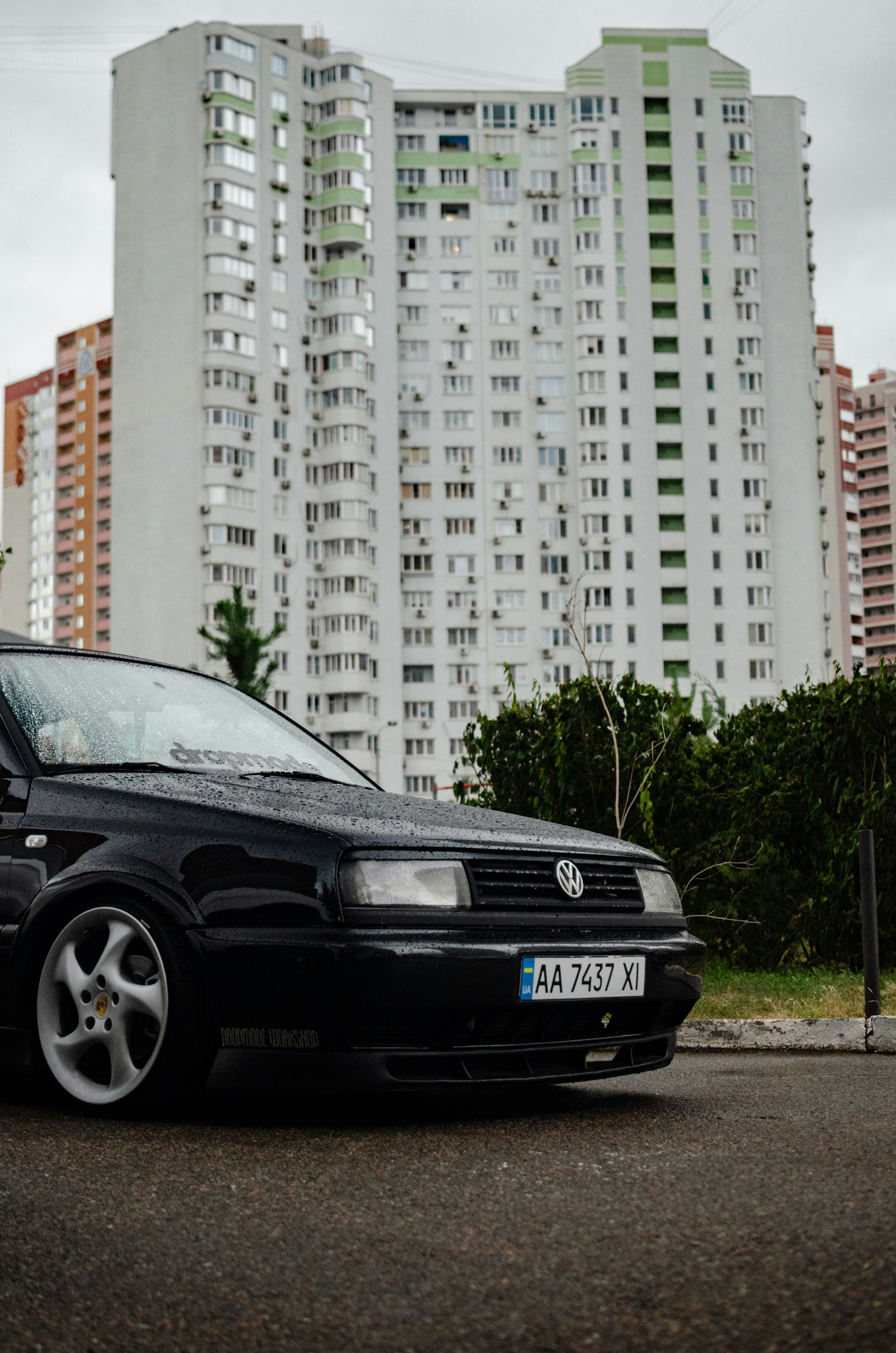 Front-Quarter Noir: VW at the Foot of Concrete Giants