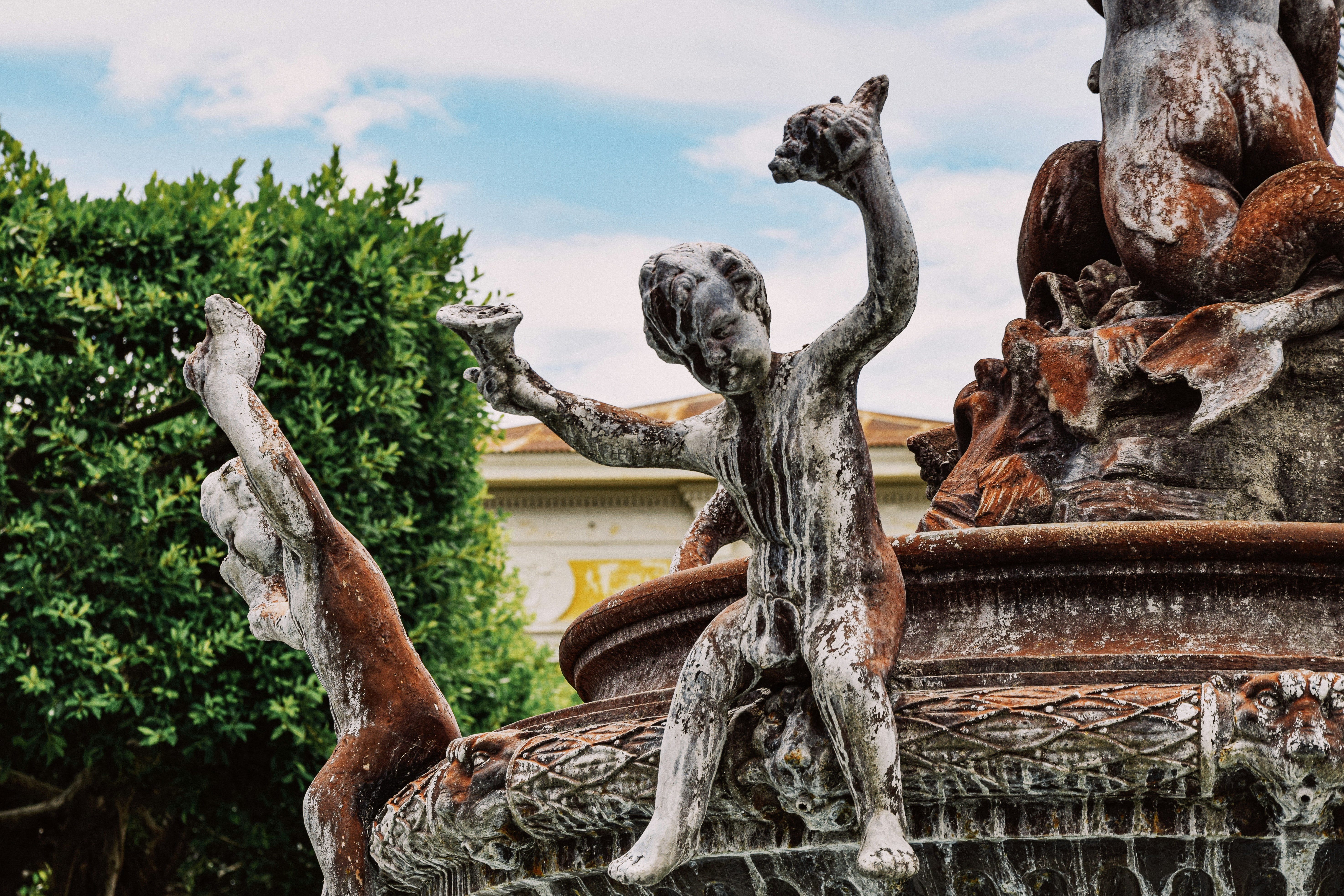 Weathered Cherub in a Fountain: Timeworn Carved Figures Guard a Grimming Basin