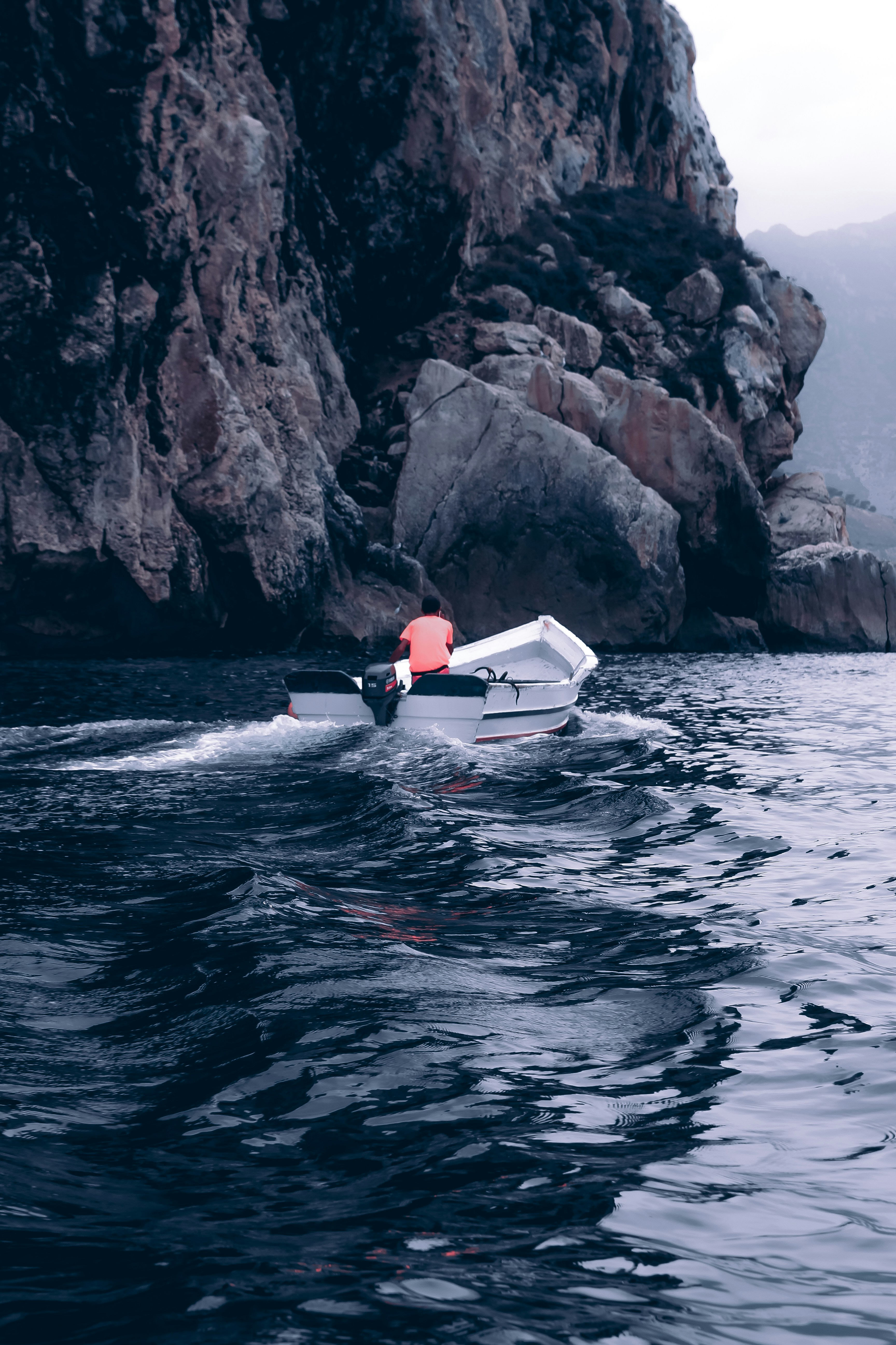 Orange Beacon on a White Boat at the Foot of a Monolithic Cliff