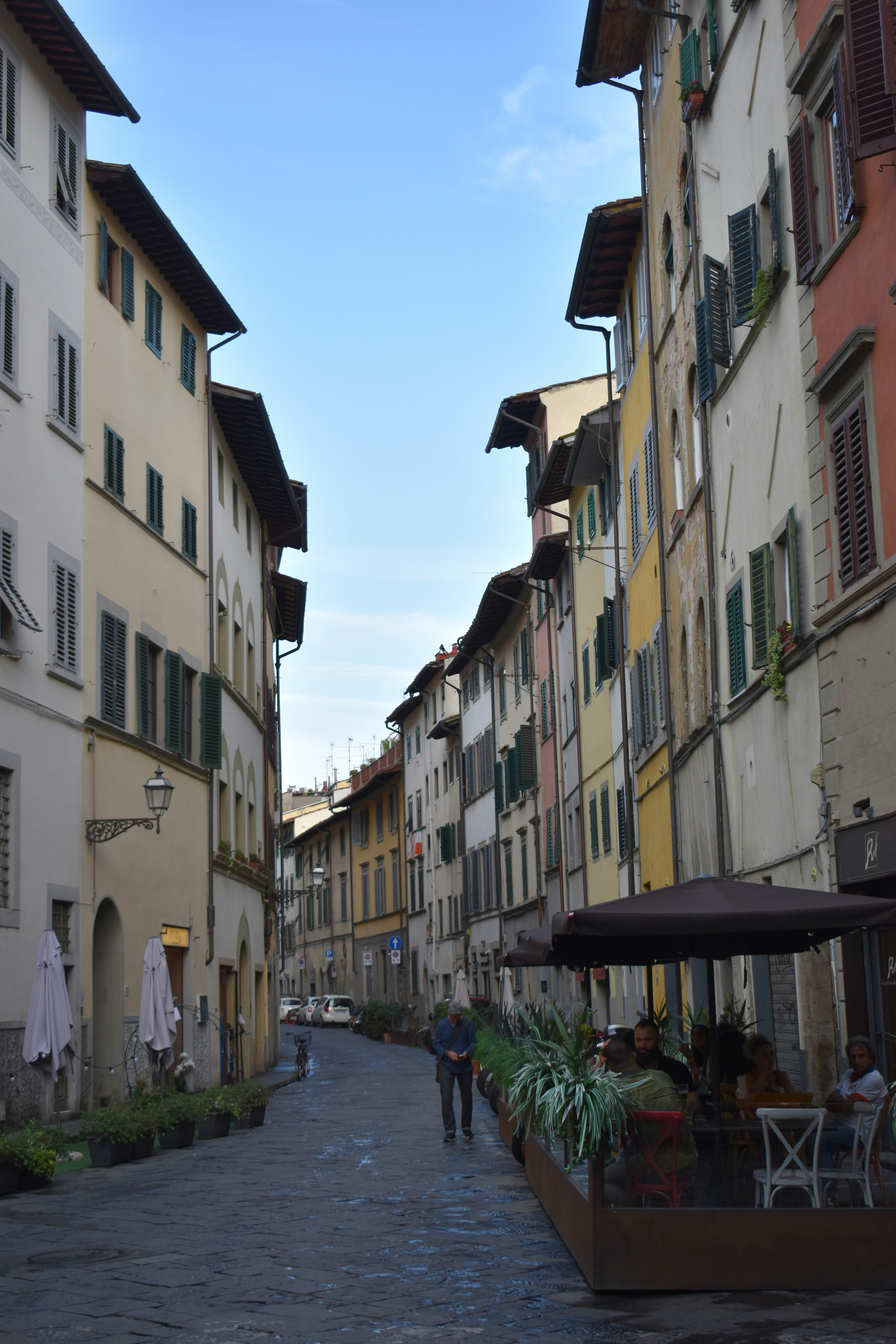 Charming Tuscan street lined with colorful buildings, inviting cafés, and a hint of local life. The scene captures the essence of everyday moments in an Italian town.