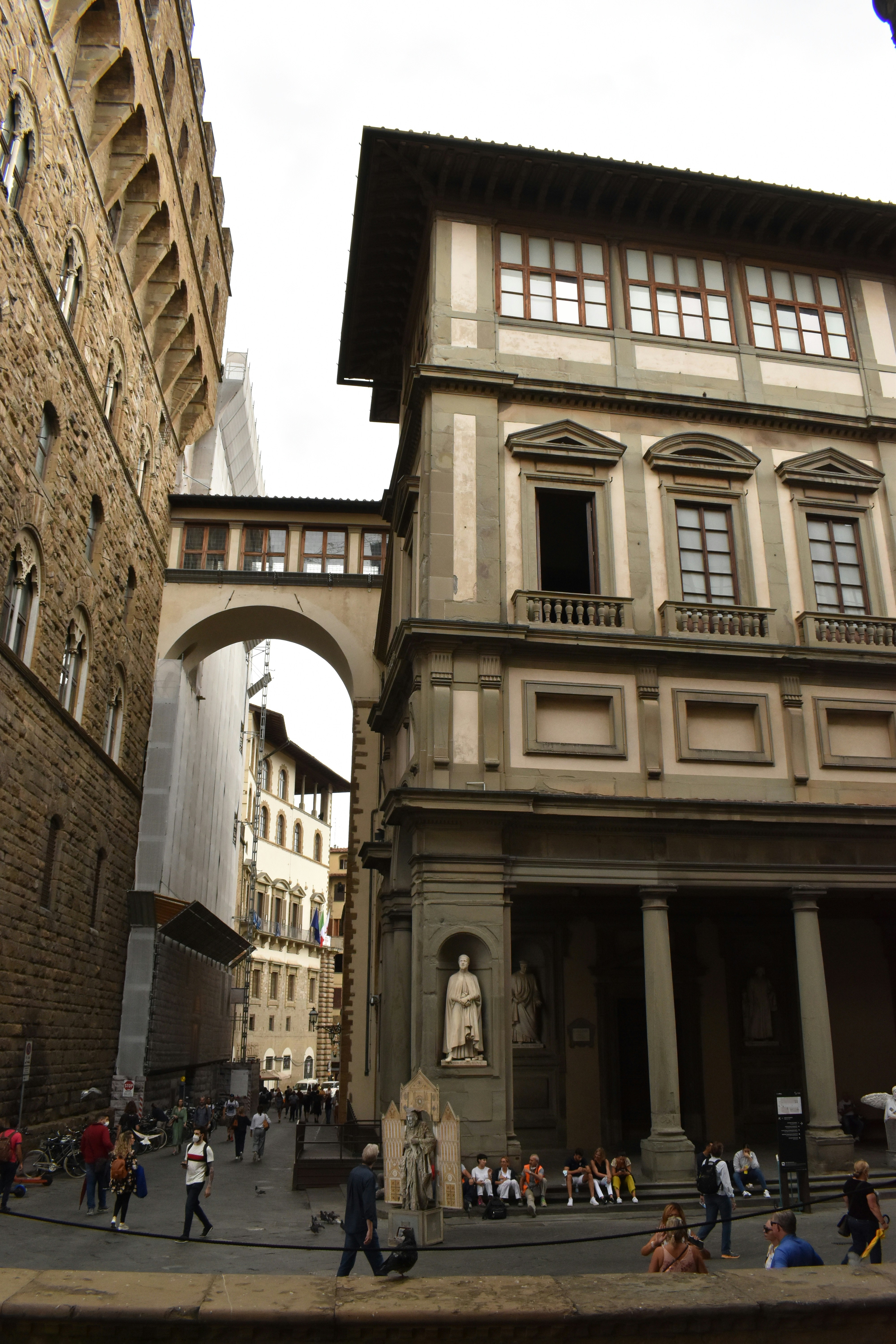 a group of people walking down a street next to tall buildingsMaria Rodideal